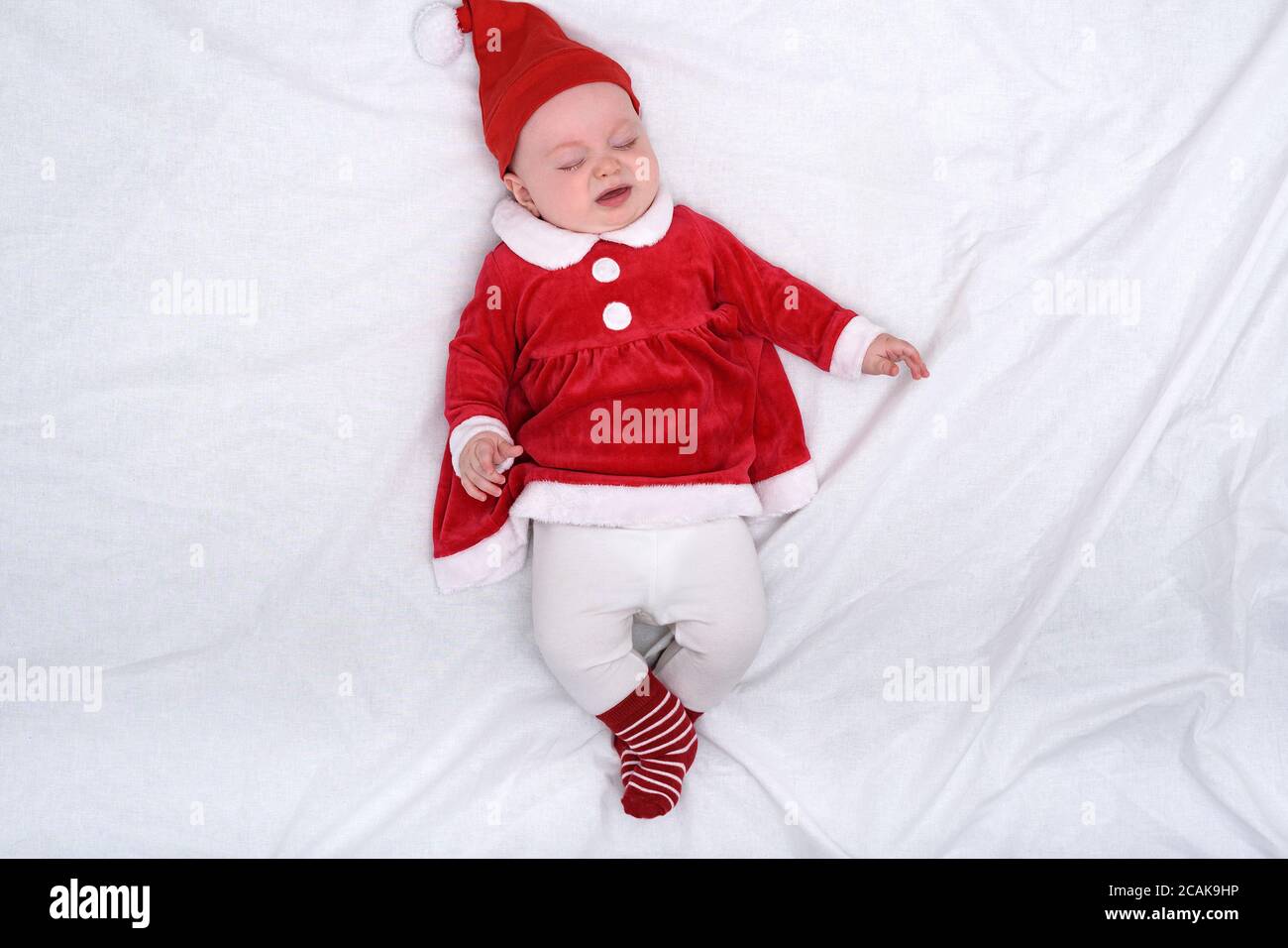 Portrait of crying little baby in a santa hat and costume. Christmas ...