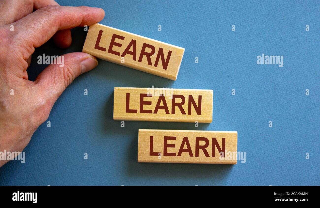 Wooden blocks form the words 'learn, learn, learn' on blue background ...