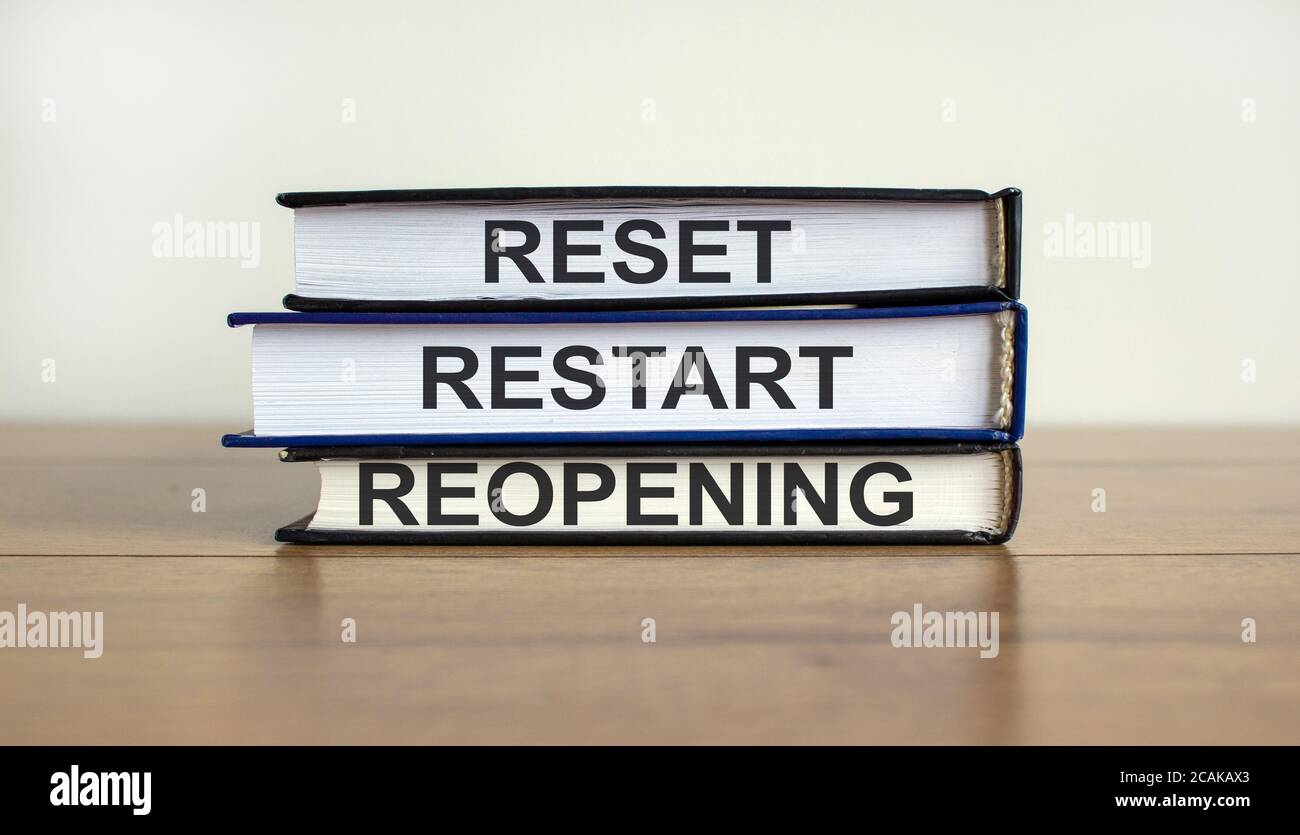 Books with text 'reset, restart, reopening' on beautiful wooden table ...