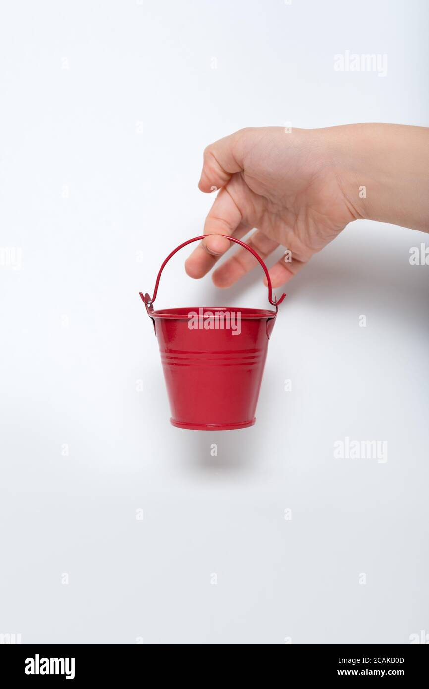 Small red bucket in children's hand on white background Stock Photo - Alamy