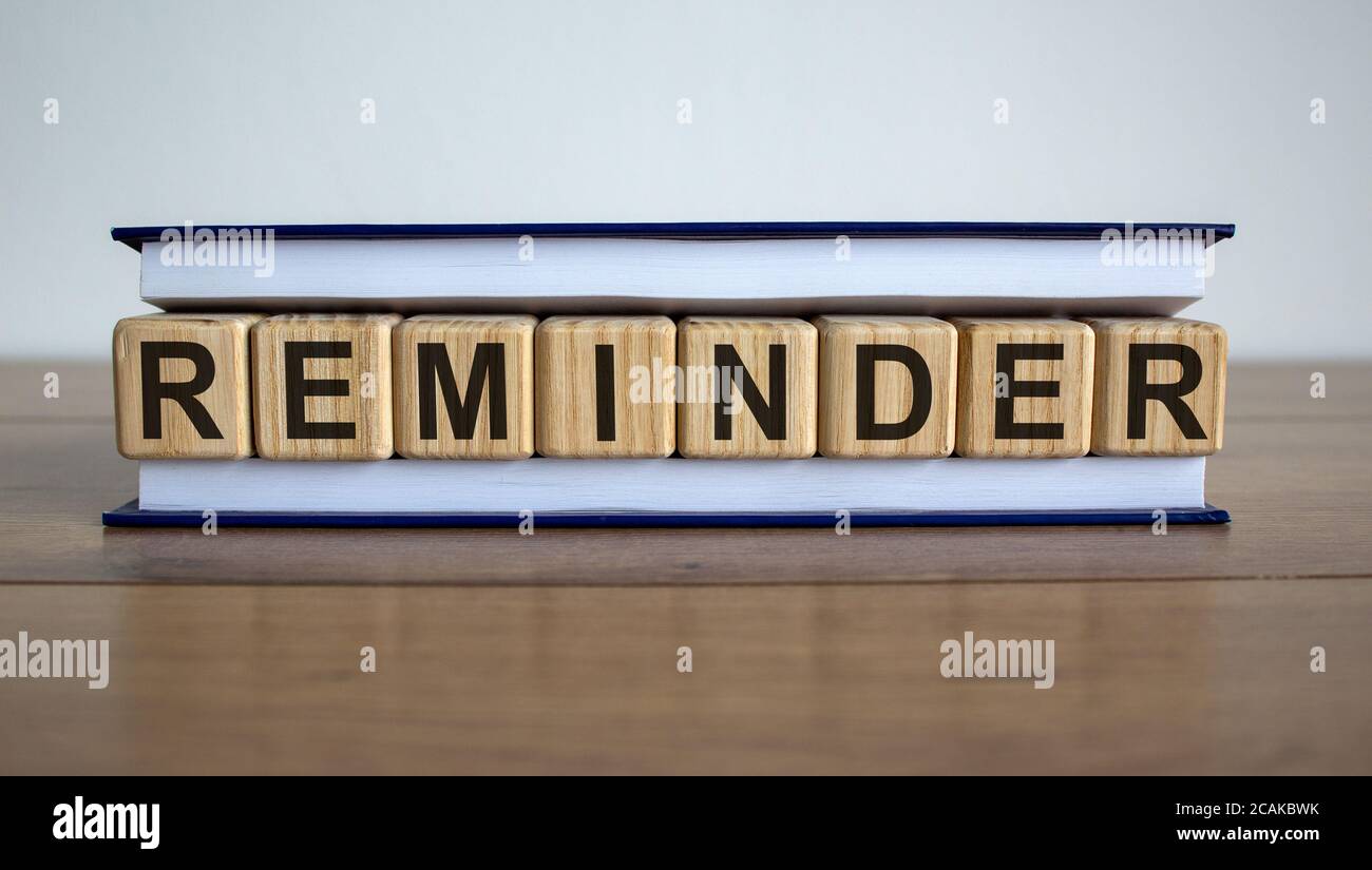 Concept word 'reminder' on wooden circles between pages of a book on a ...