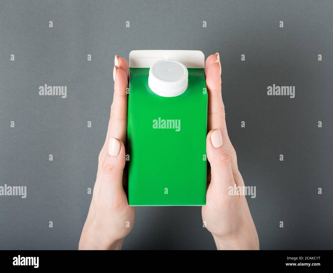 Green carton box or packaging of tetra pack with a cap in a female ...