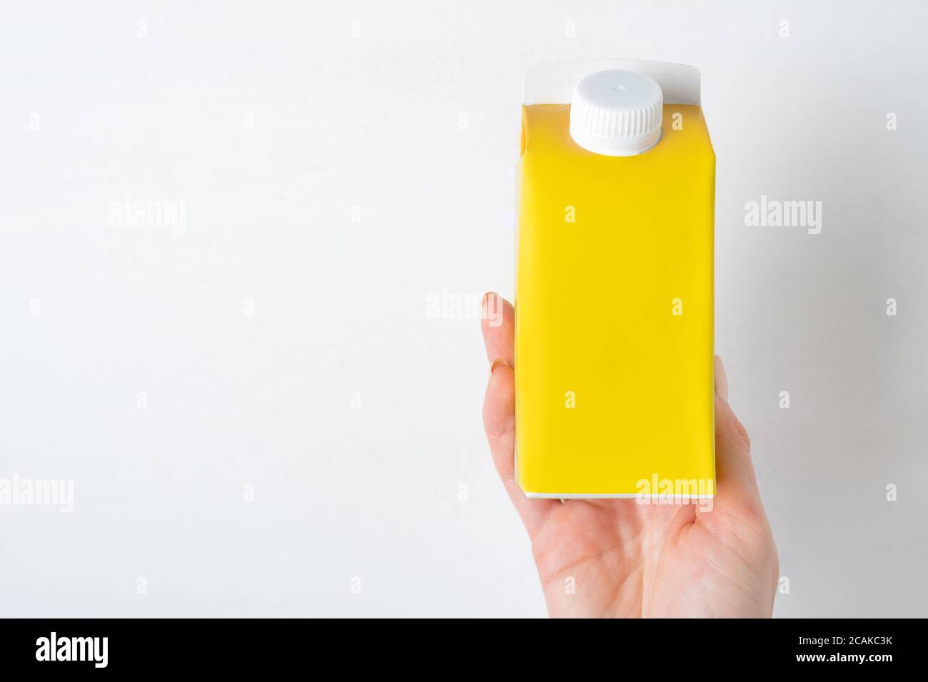 Yellow carton box or packaging of tetra pack with a cap in a female ...