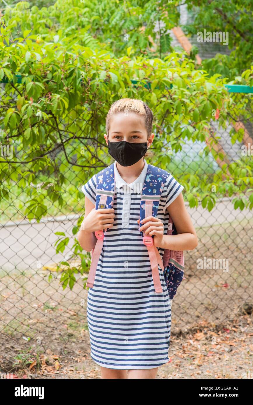 Schoolgirl girl in a black protective mask with a backpack. Schoolgirl ...