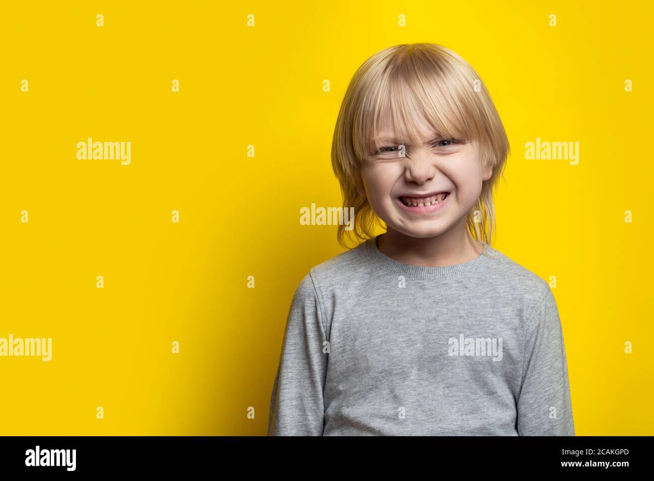 Fair-haired boy make face. Portrait of blond boy on yellow background ...