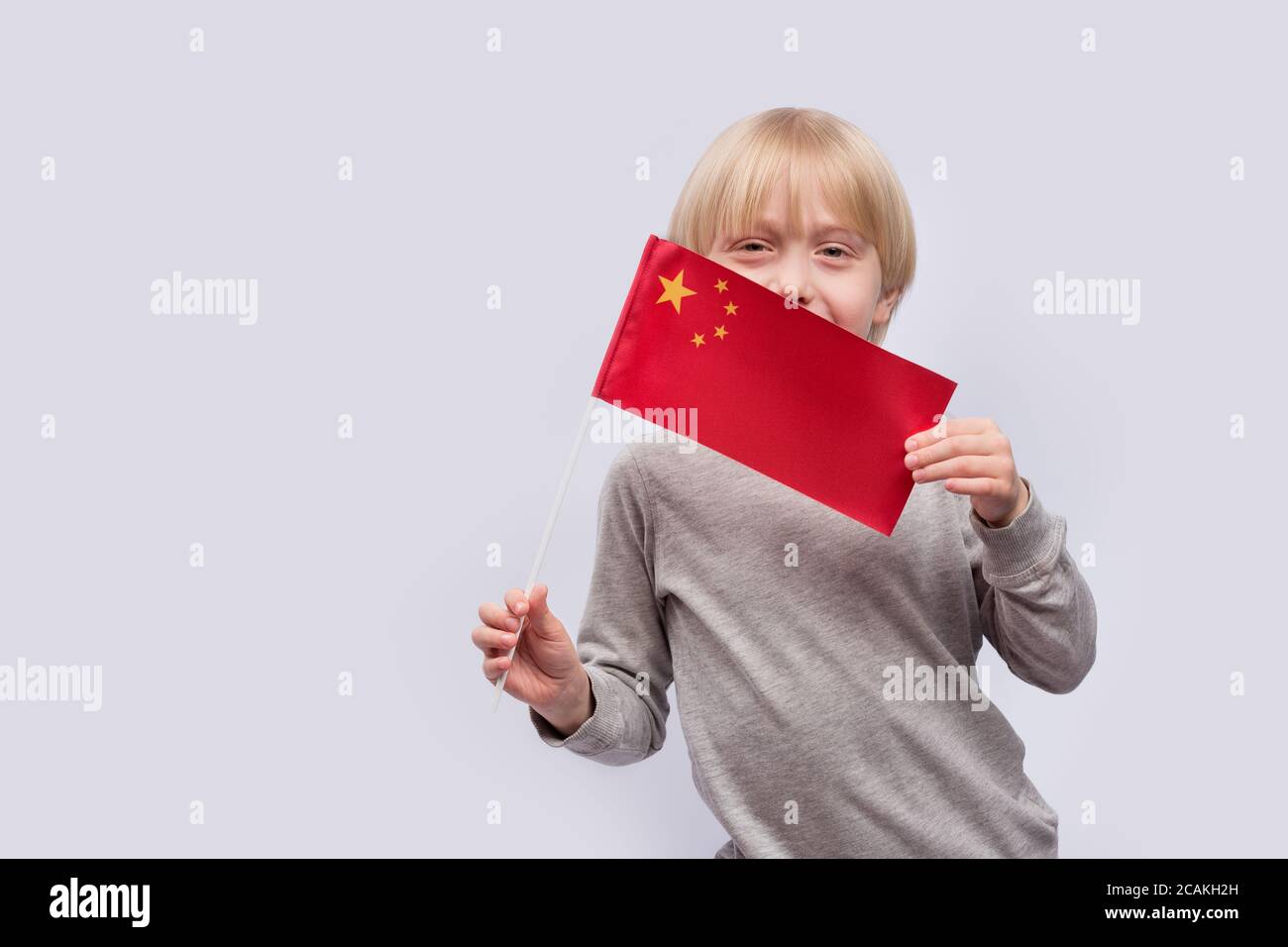 Portrait of child on white background with flag of China in hands ...