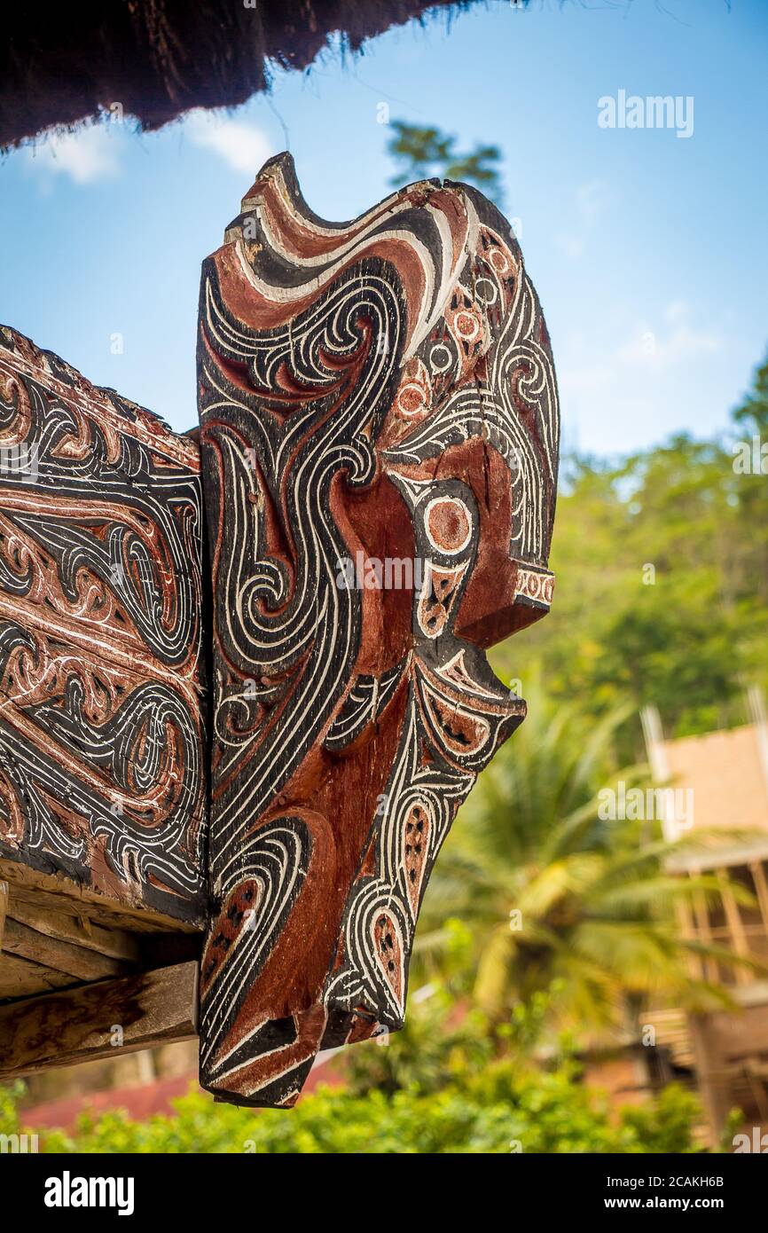A wooden Bataknese style sculpture of a head on the end of a house ...