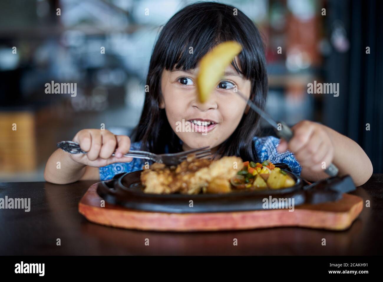 Smiling Cute girl eating Steak and showing slice of fried potatoes ...
