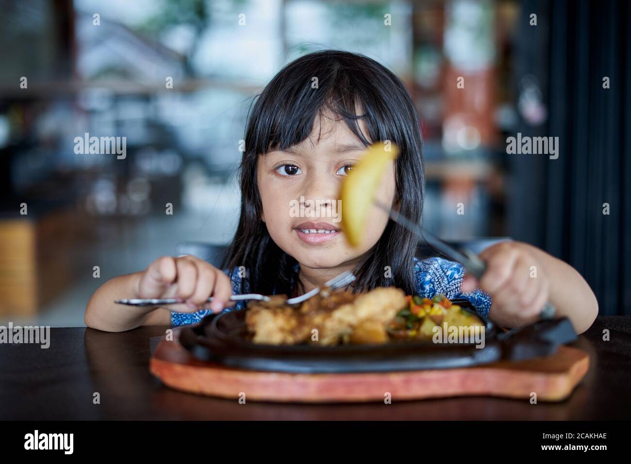 Smiling Cute girl eating Steak and showing slice of fried potatoes ...