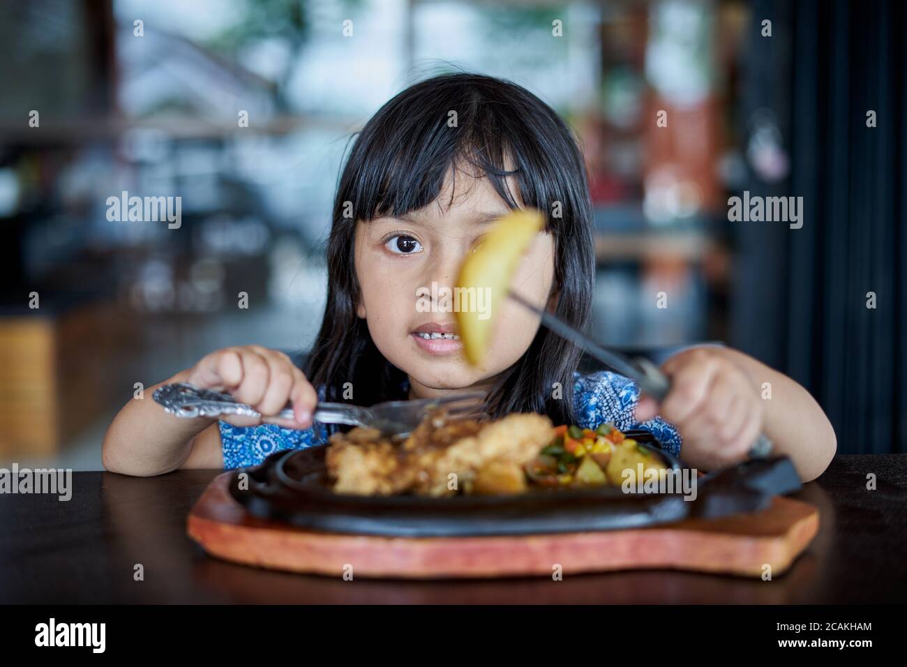Smiling Cute girl eating Steak and showing slice of fried potatoes ...