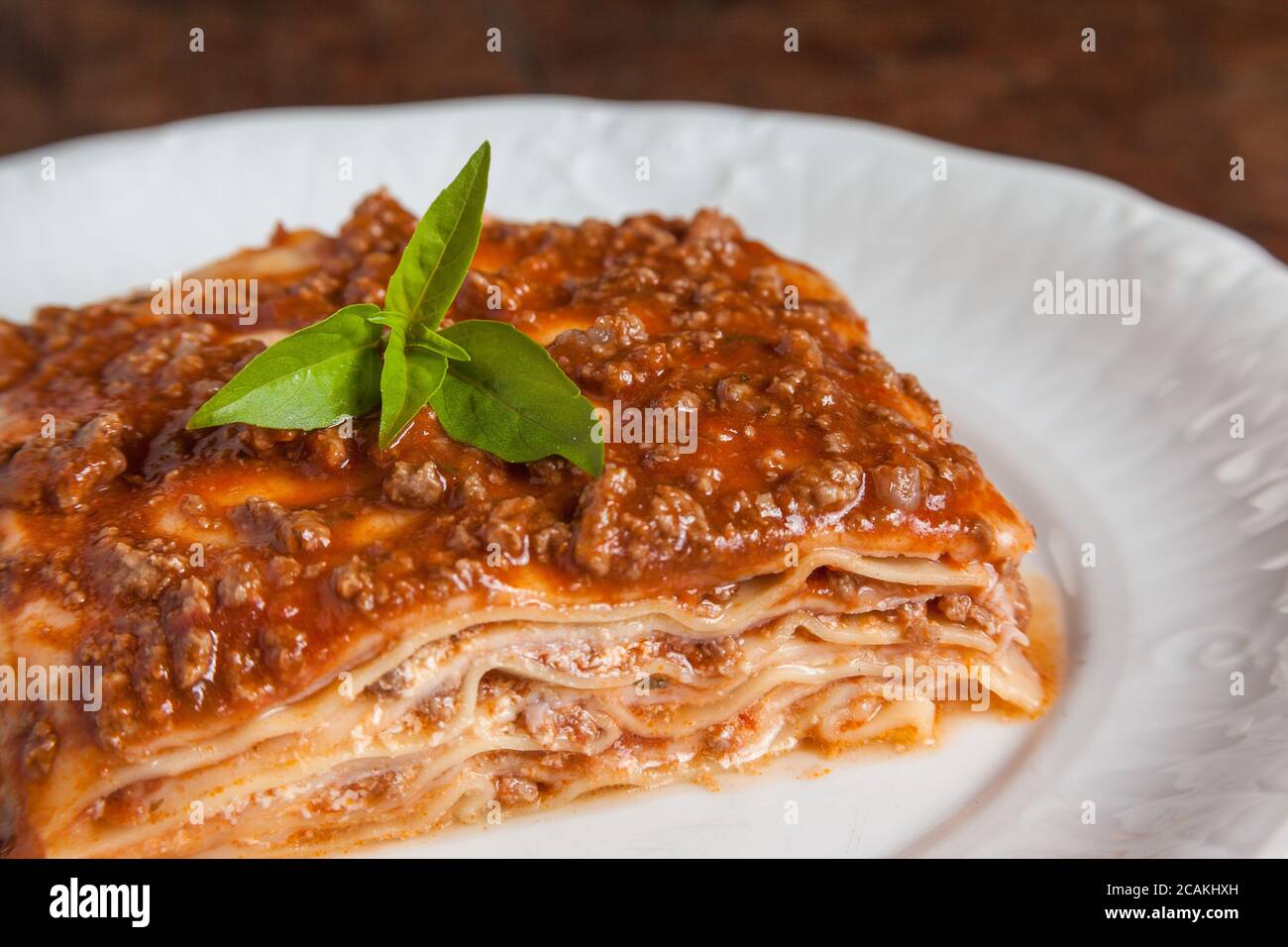 A slice of lasagna on a wood table Stock Photo - Alamy