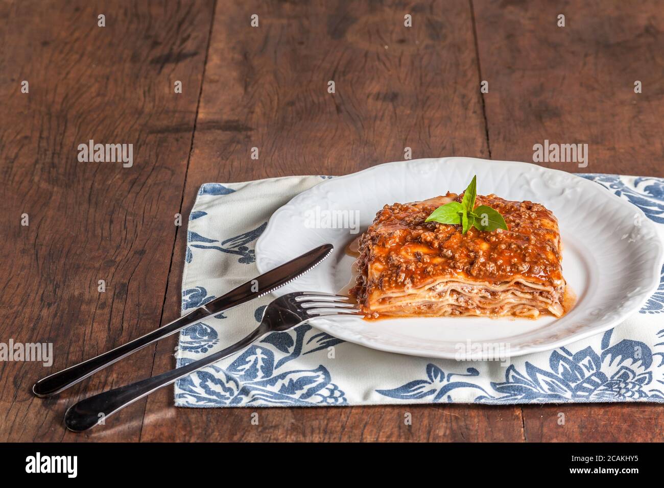 A slice of lasagna on a wood table Stock Photo - Alamy