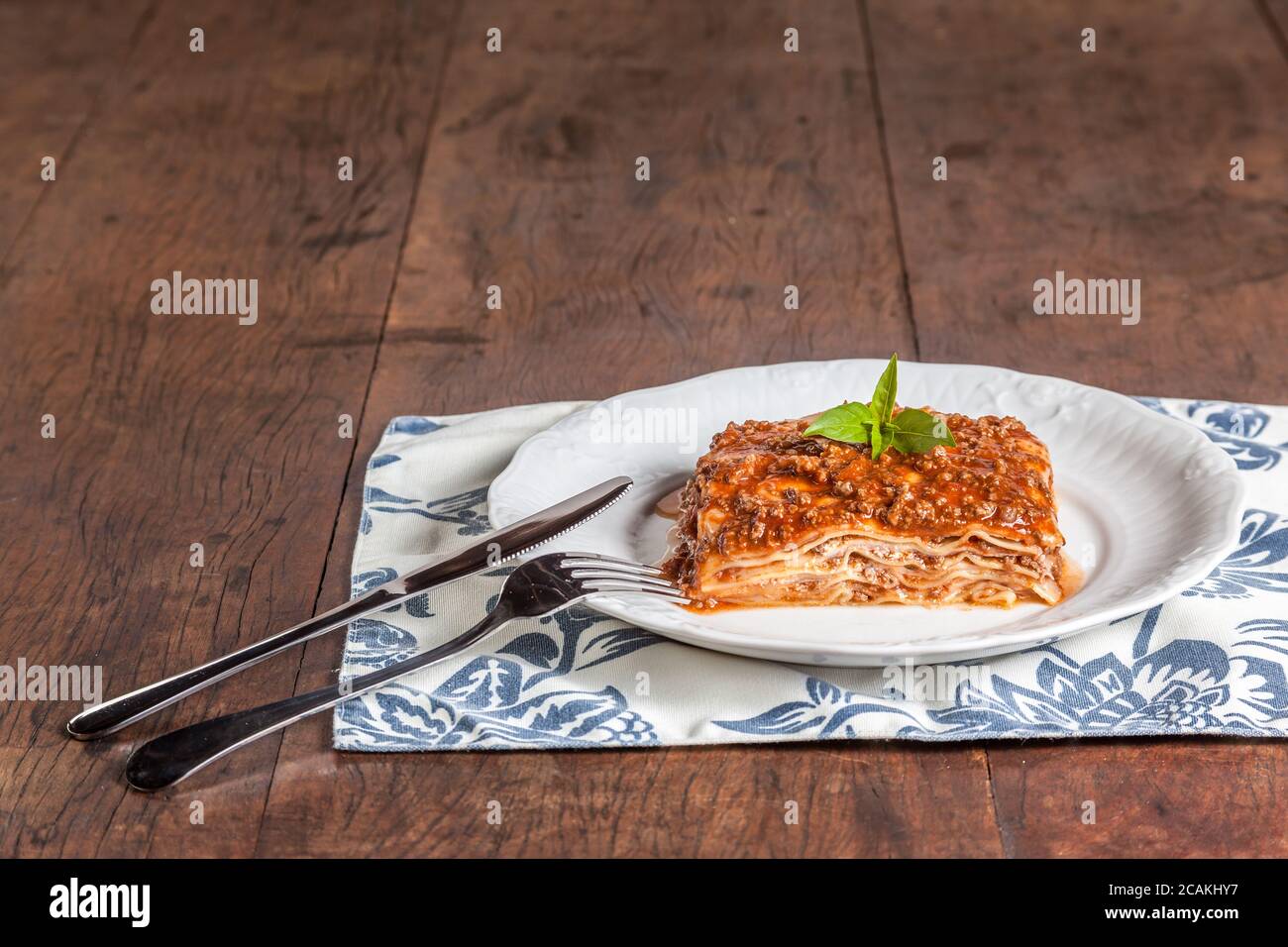 A slice of lasagna on a wood table Stock Photo - Alamy