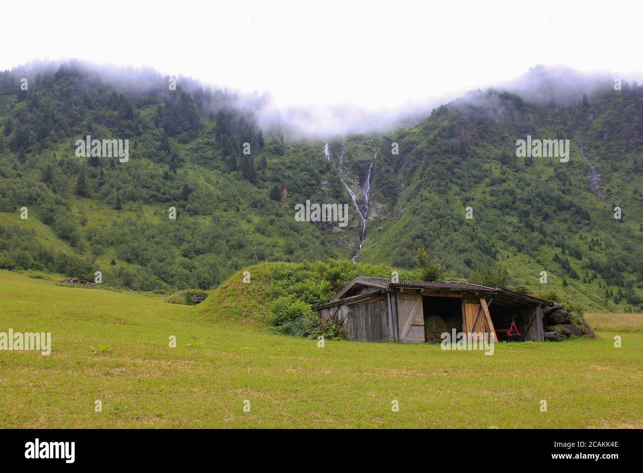 Charming wooden barn hidden in a mountain alpine valley with green ...