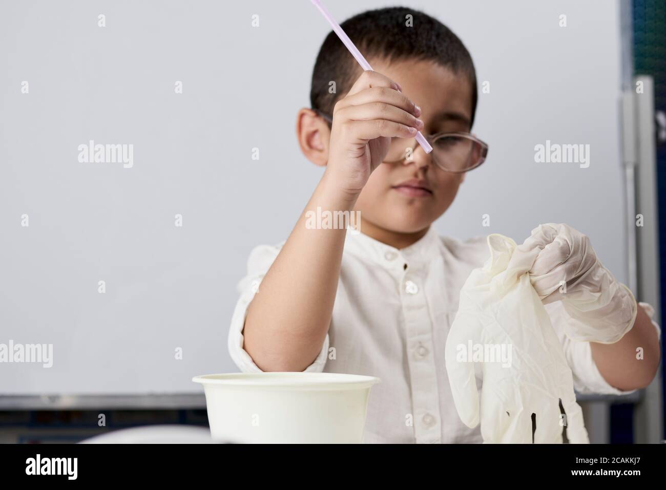 Little boy scientist in white making experiments against the white ...
