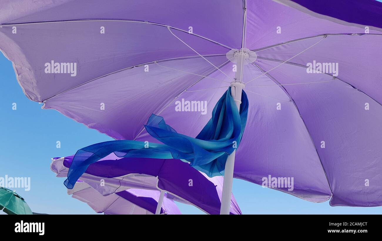 Bright blue silk scarf is waving on wind with shiny violet beach ...