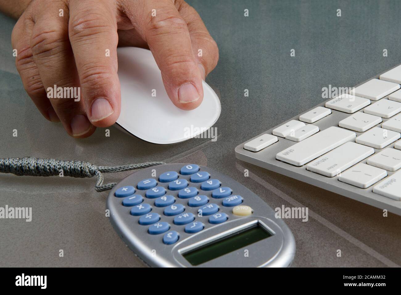 hand holding mouse on table with keyboard and calculator beside Stock ...