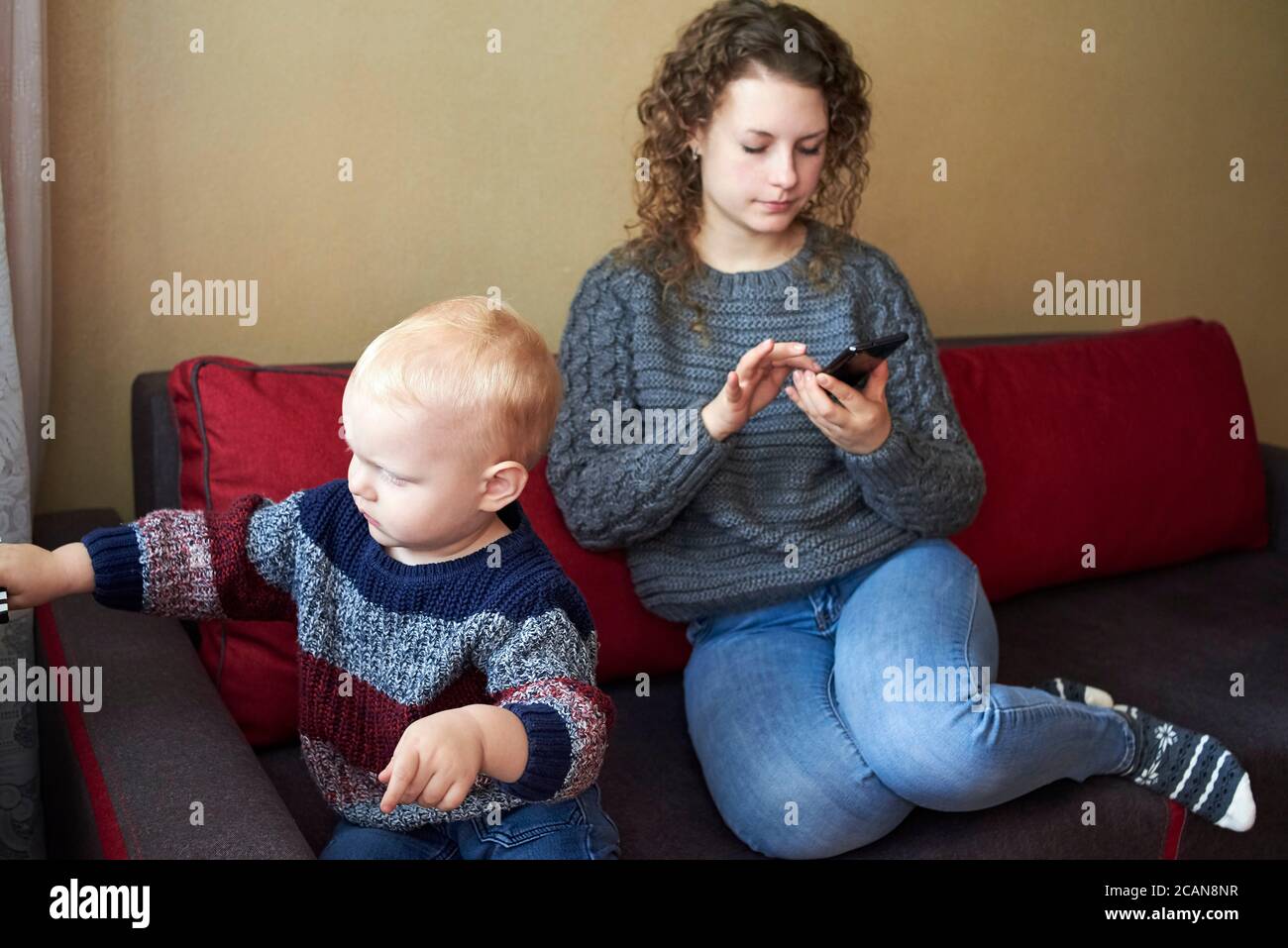 Mother is indifferent to her little son, mom looks at the smartphone ...