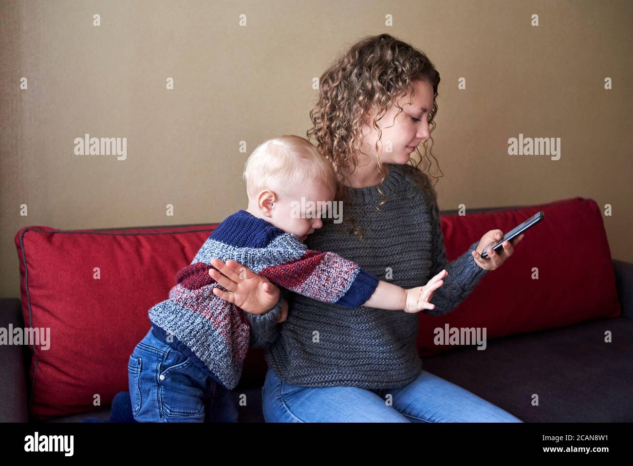 Mother is indifferent to her little son, mom looks at the smartphone ...