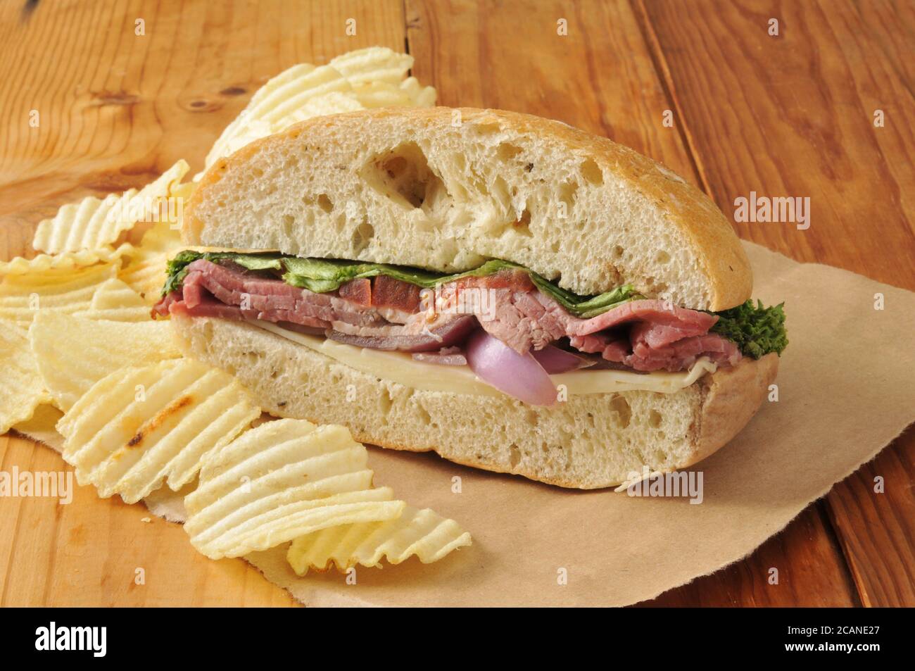 A roast beef sandwich on a ciabatta bun with potato chips Stock Photo ...