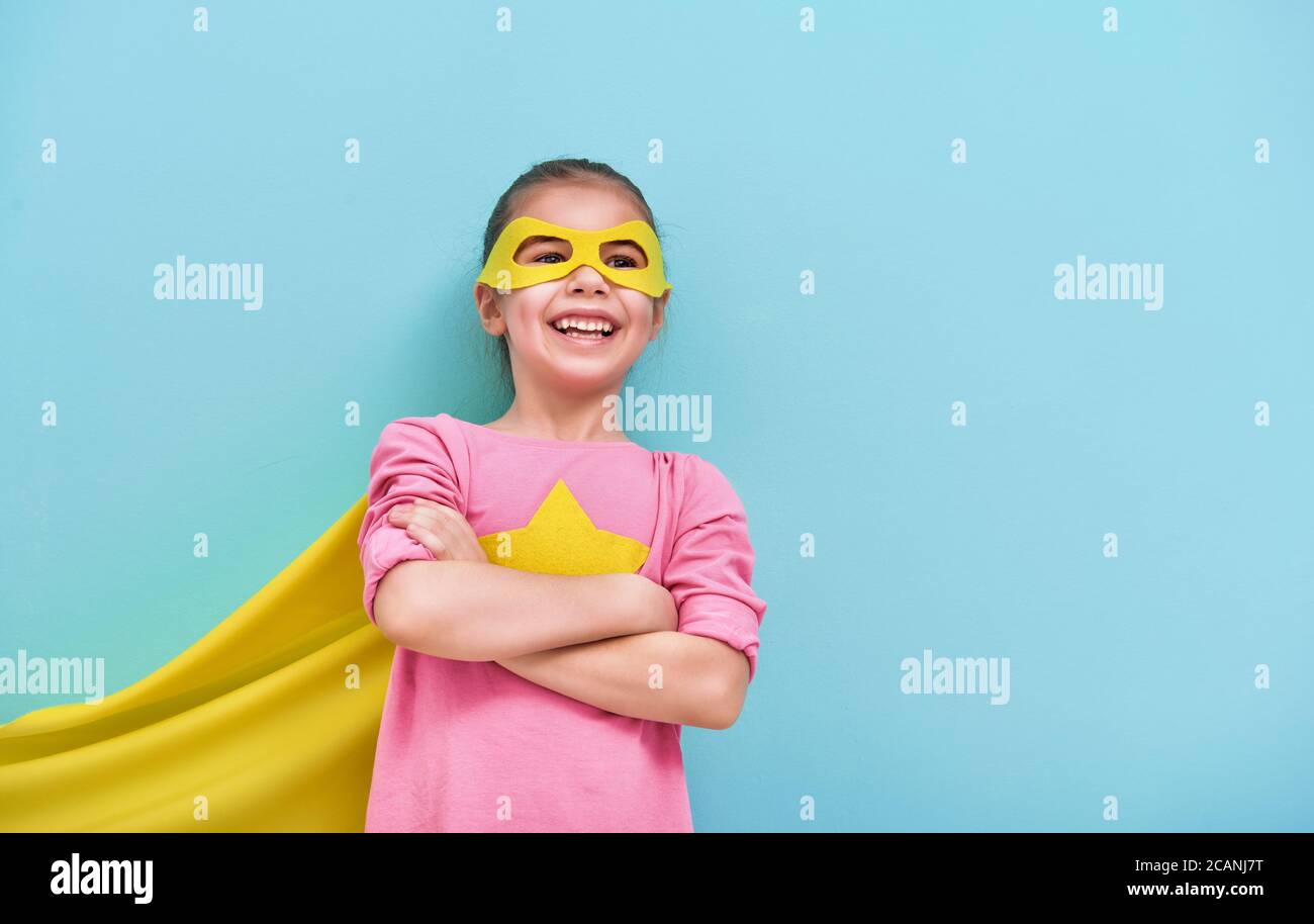 Little child plays superhero. Kid on the background of bright blue wall ...