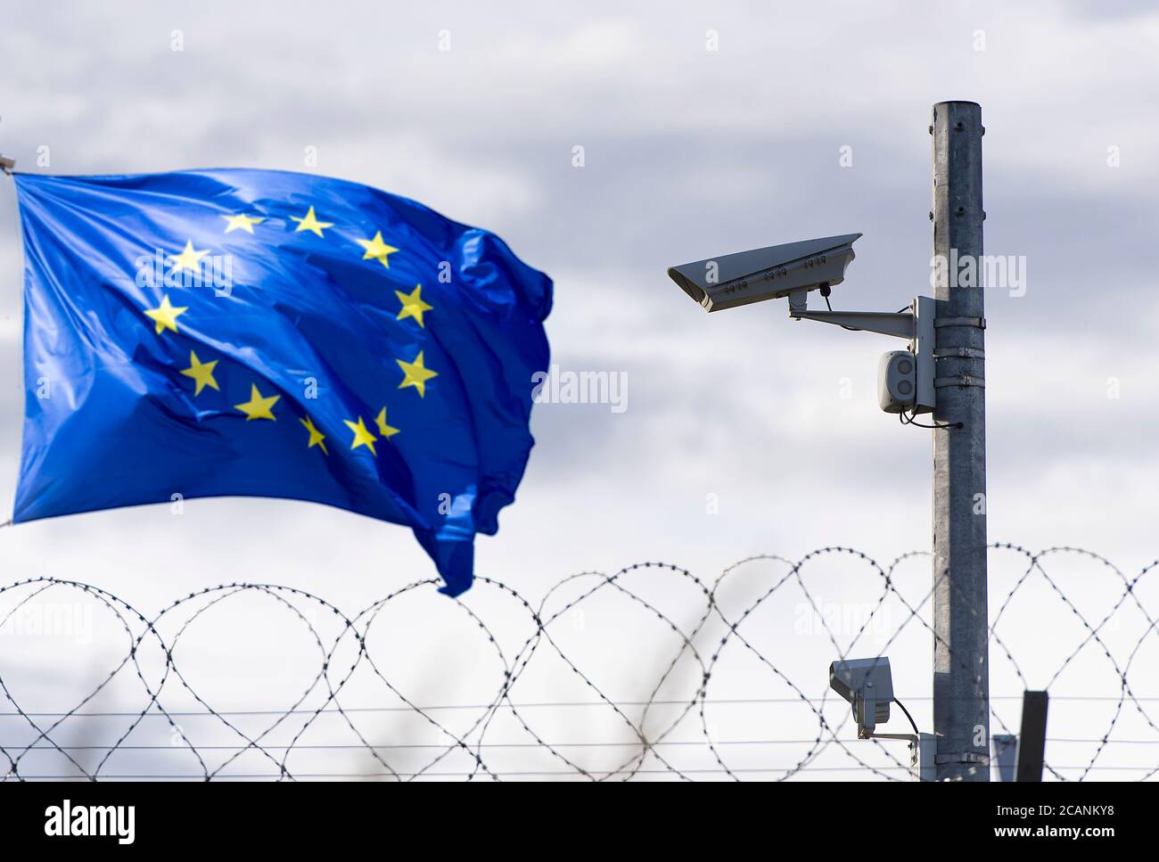European union flag and EU border with surveillance camera and barbed ...