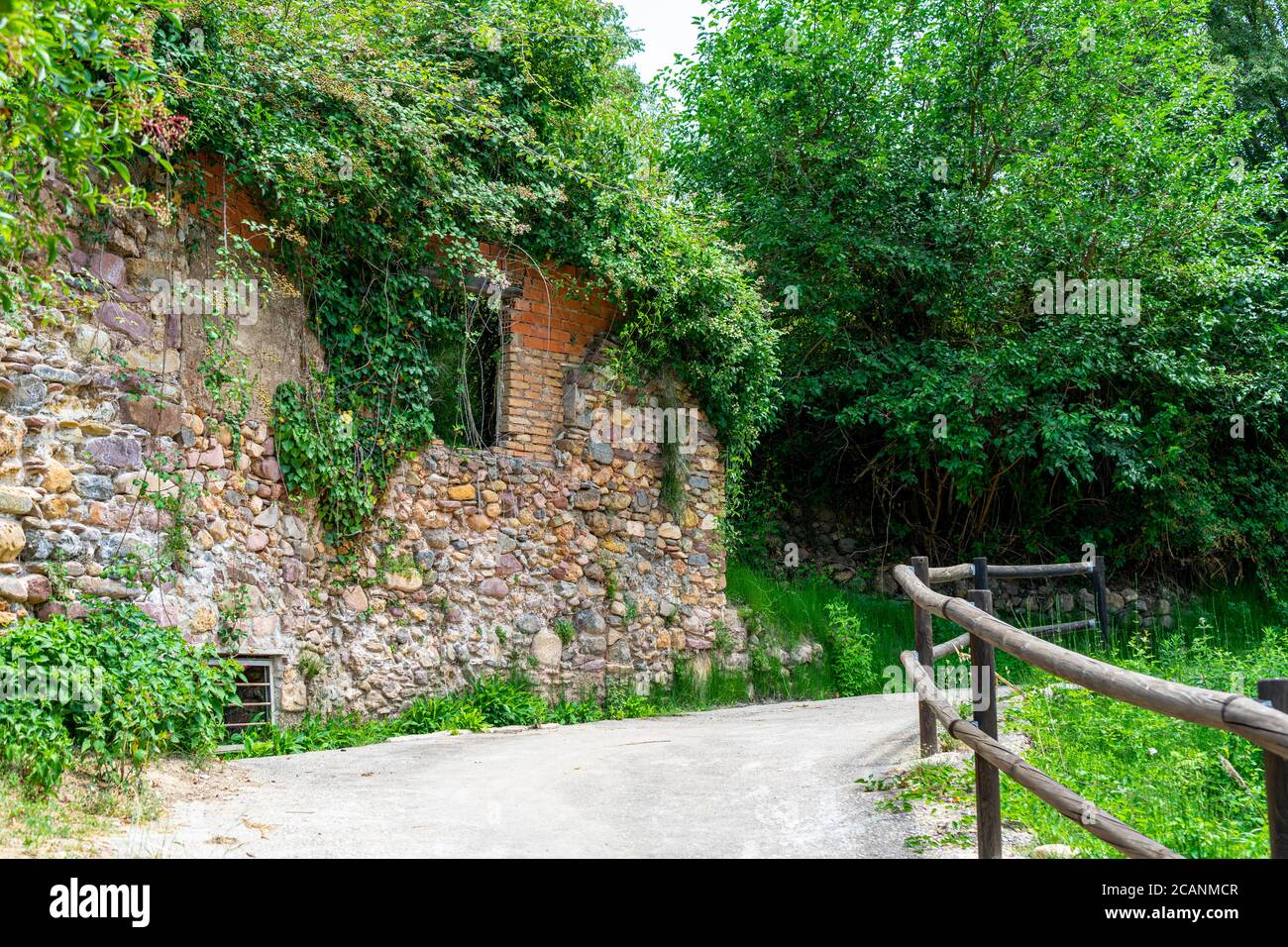View of a nice country road with a stone wall, a wooden railing and ...