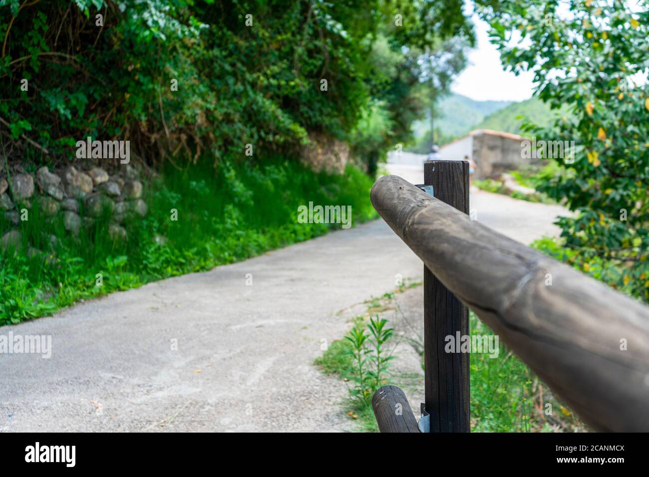 View of a nice country road with a stone wall, a wooden railing and ...