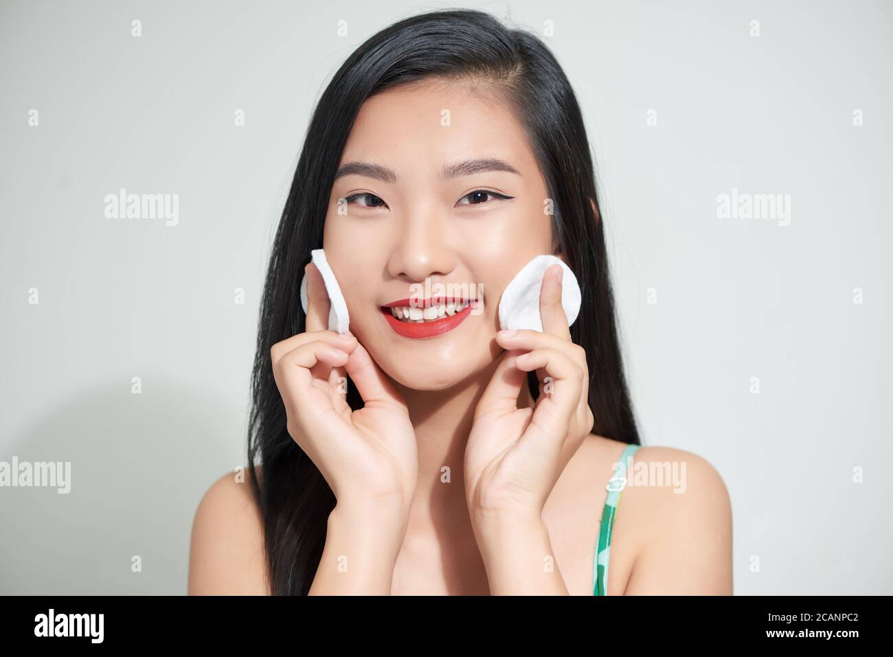 Pretty beauty young Asian woman cleaning her face with cotton pad over ...