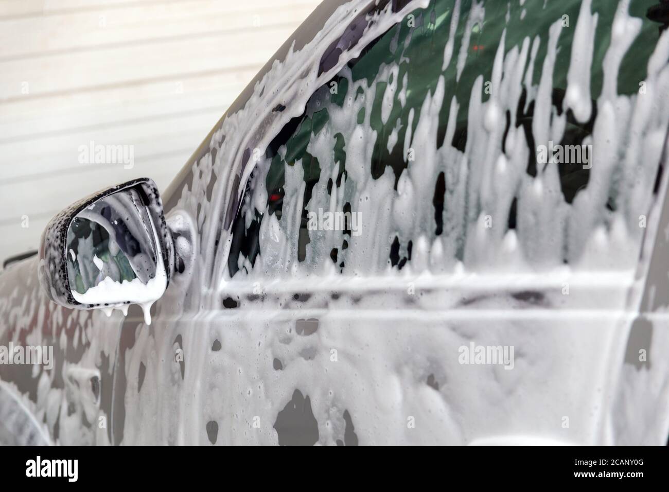 Closeup view of motor car window with layer of soap sud during car wash ...