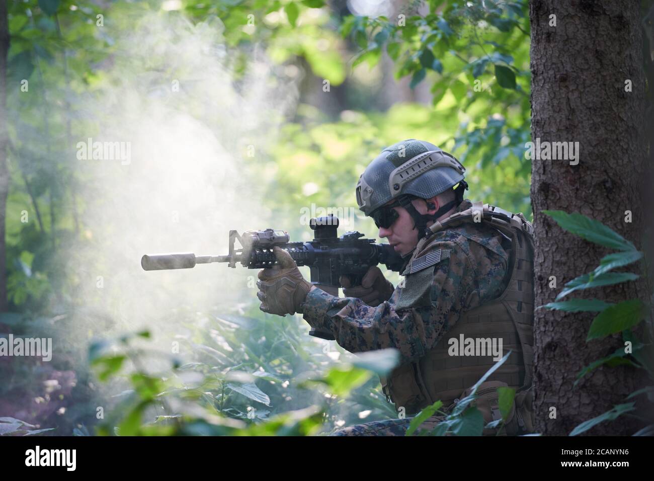 modern warfare soldier in action aiming at weapon laser sight optics in combat position while ...