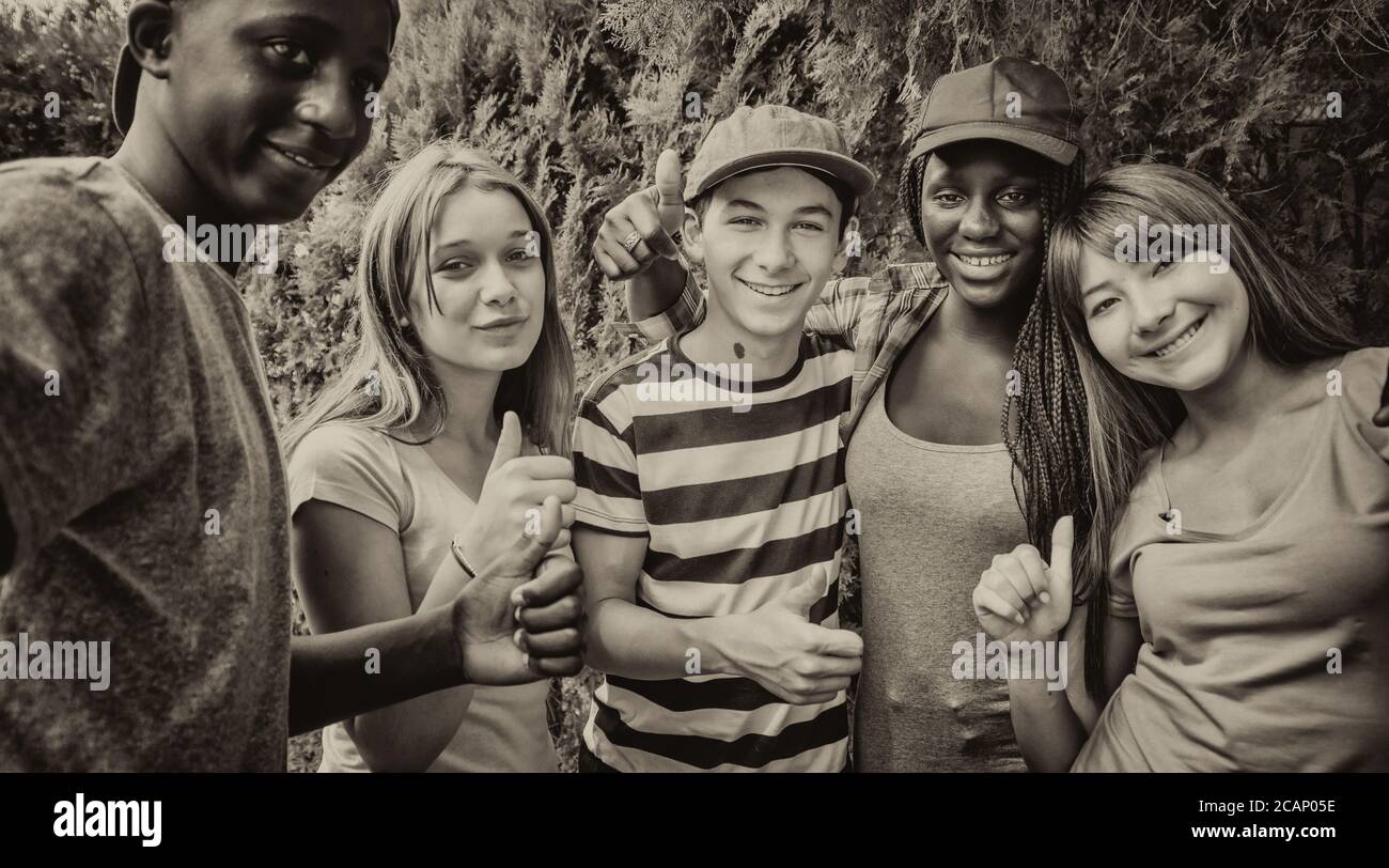 Happy group of mixed races teenagers standing on the grass in the ...