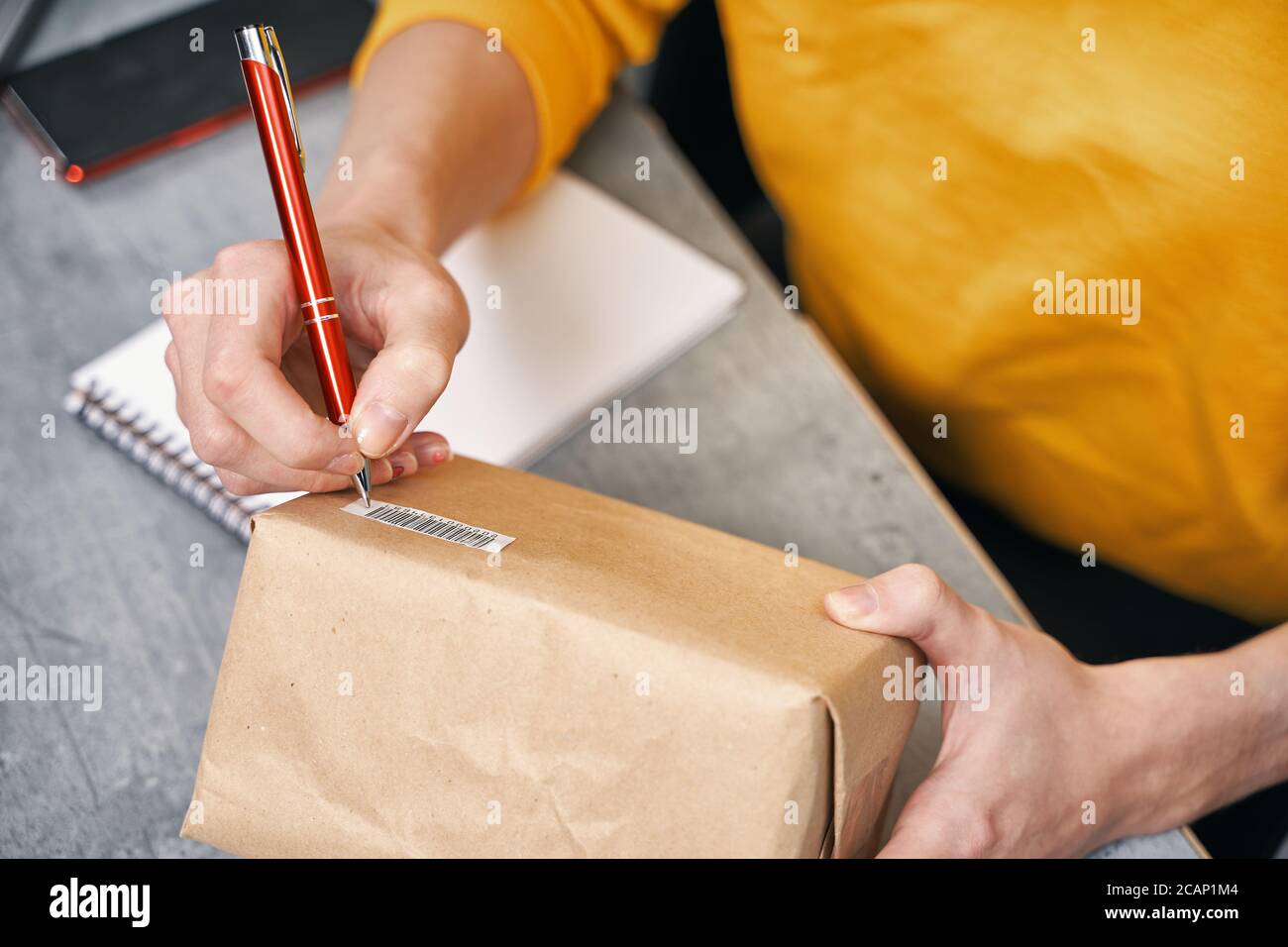 Woman writing address on the parcel. Working from home in quarantine ...