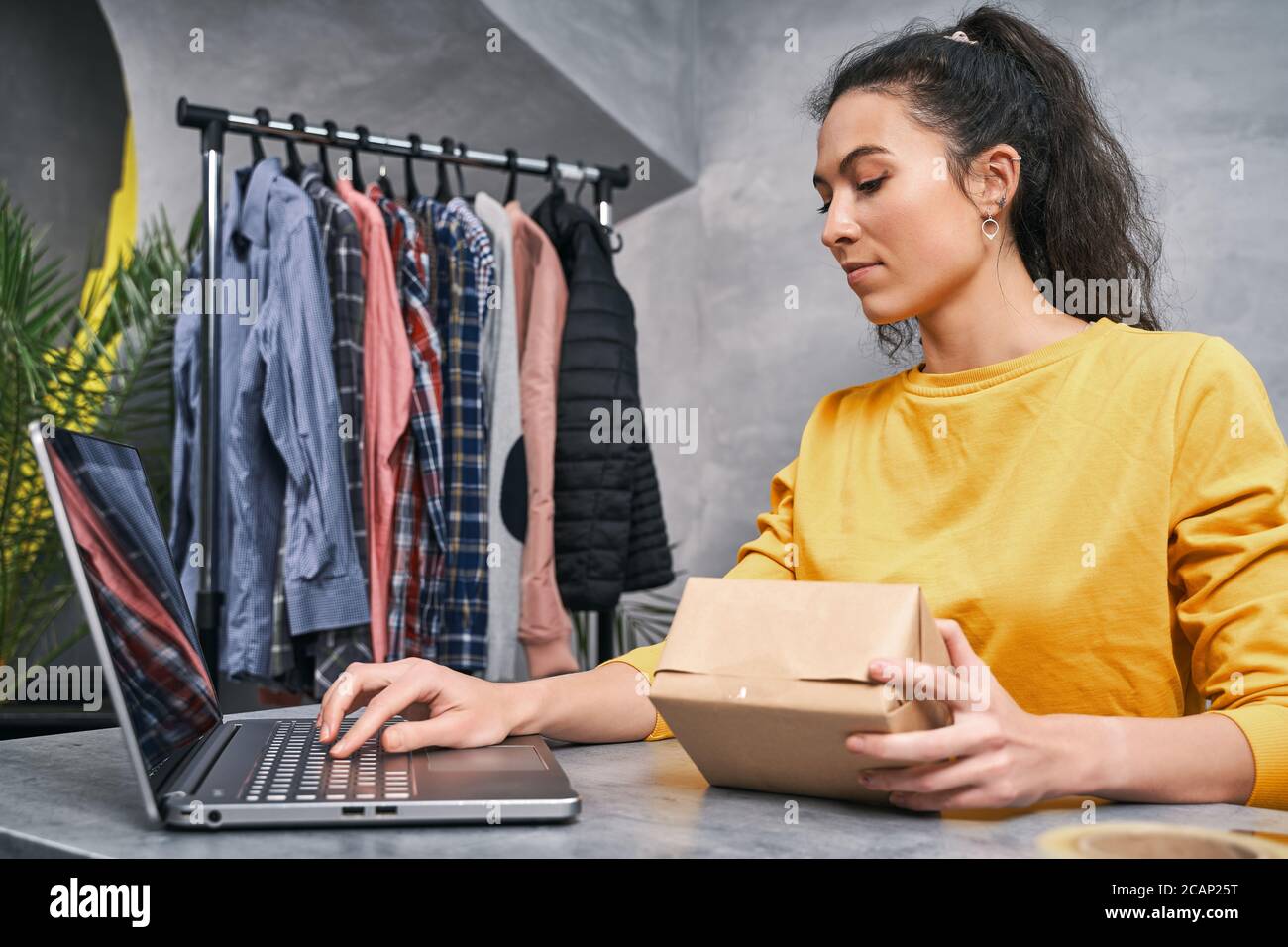 Woman sending parcel using her laptop. Working from home Stock Photo ...