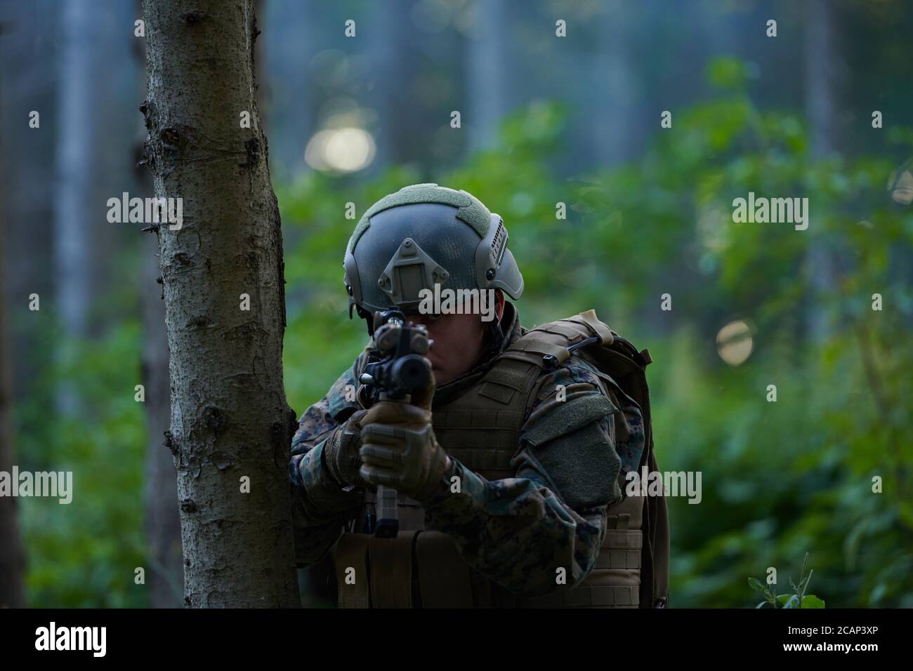 modern warfare soldier in action aiming at weapon laser sight optics in combat position while ...
