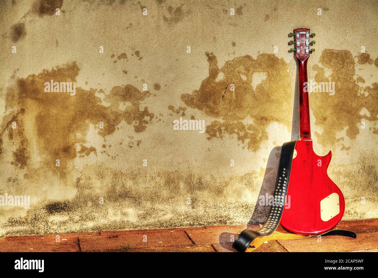 rear view of an electric guitar leaned on a rustic wall in hdr tone ...
