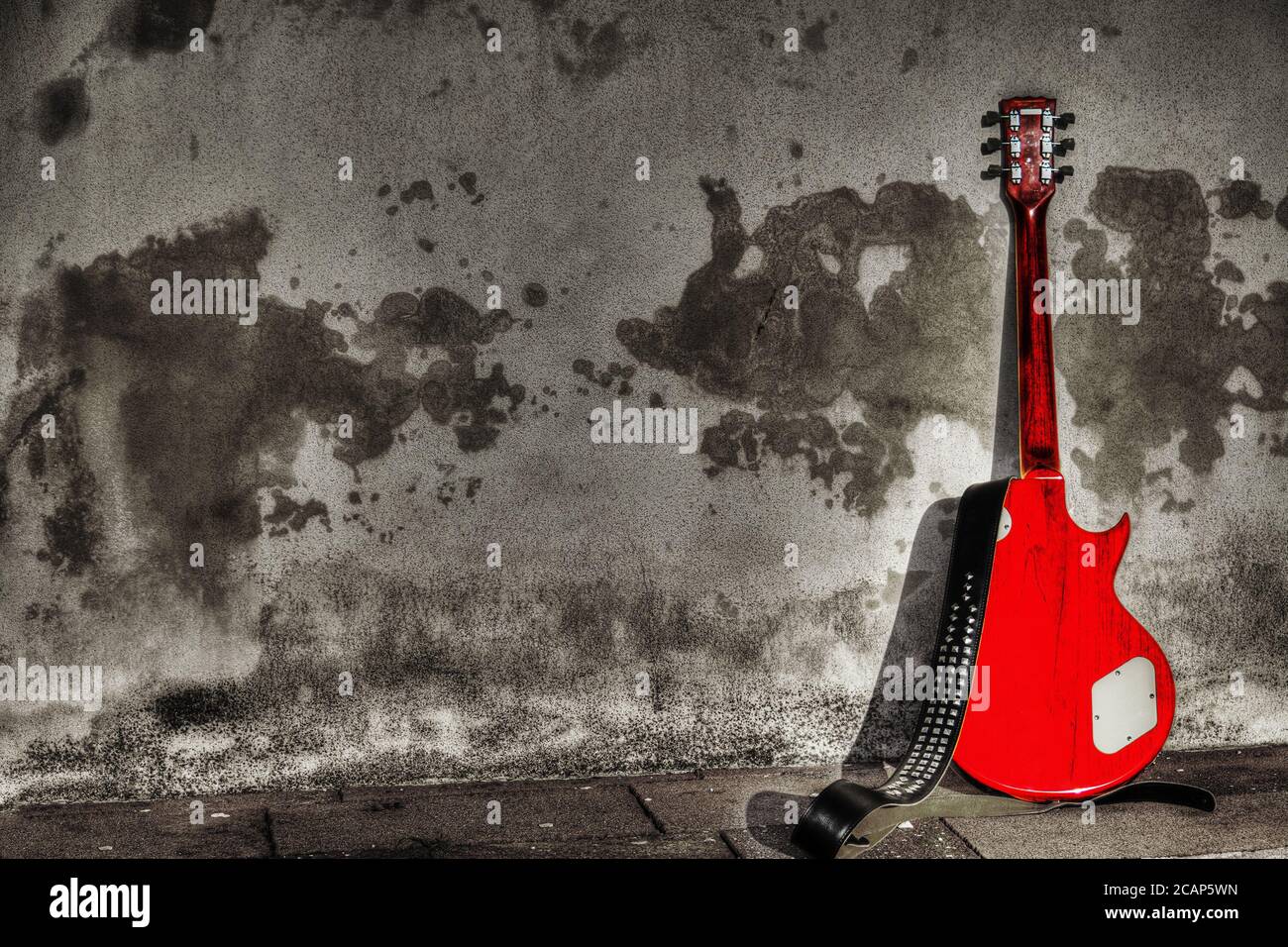 rear view of an electric guitar leaned on a rustic wall in selective ...