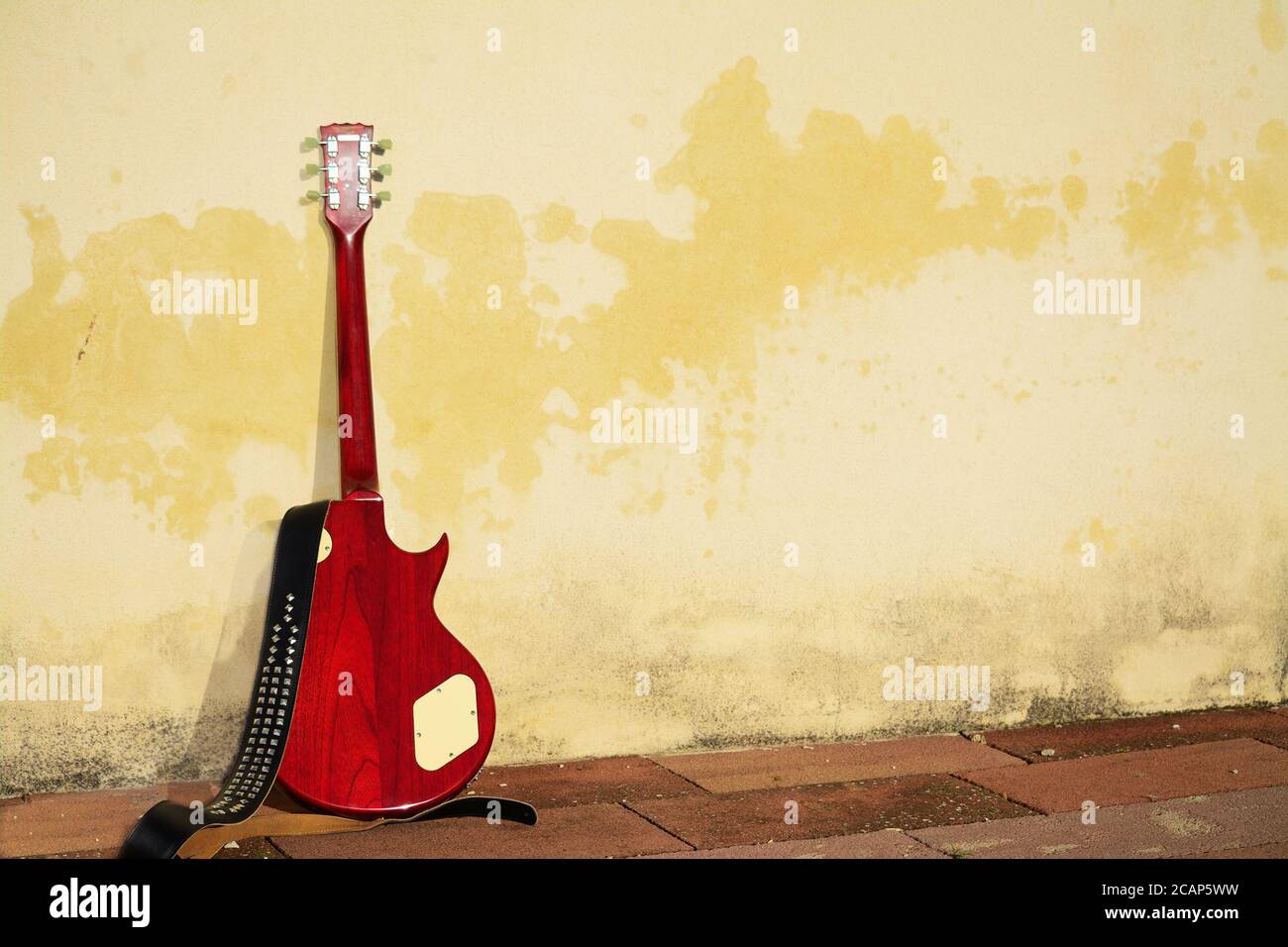 rear view of an electric guitar leaned on a rustic wall Stock Photo - Alamy
