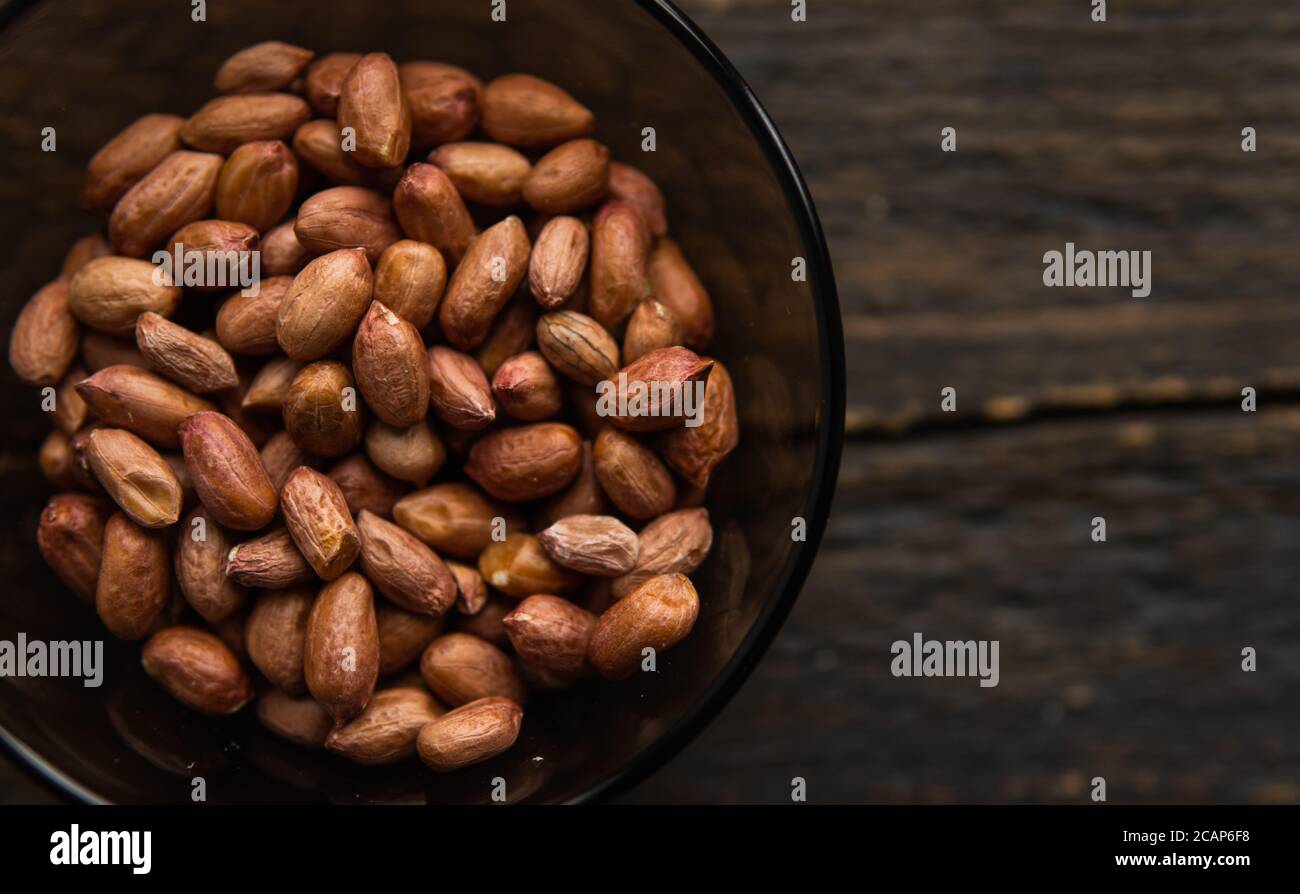 Peanut nuts in a small plate on a vintage wooden table. Peanuts nut is ...