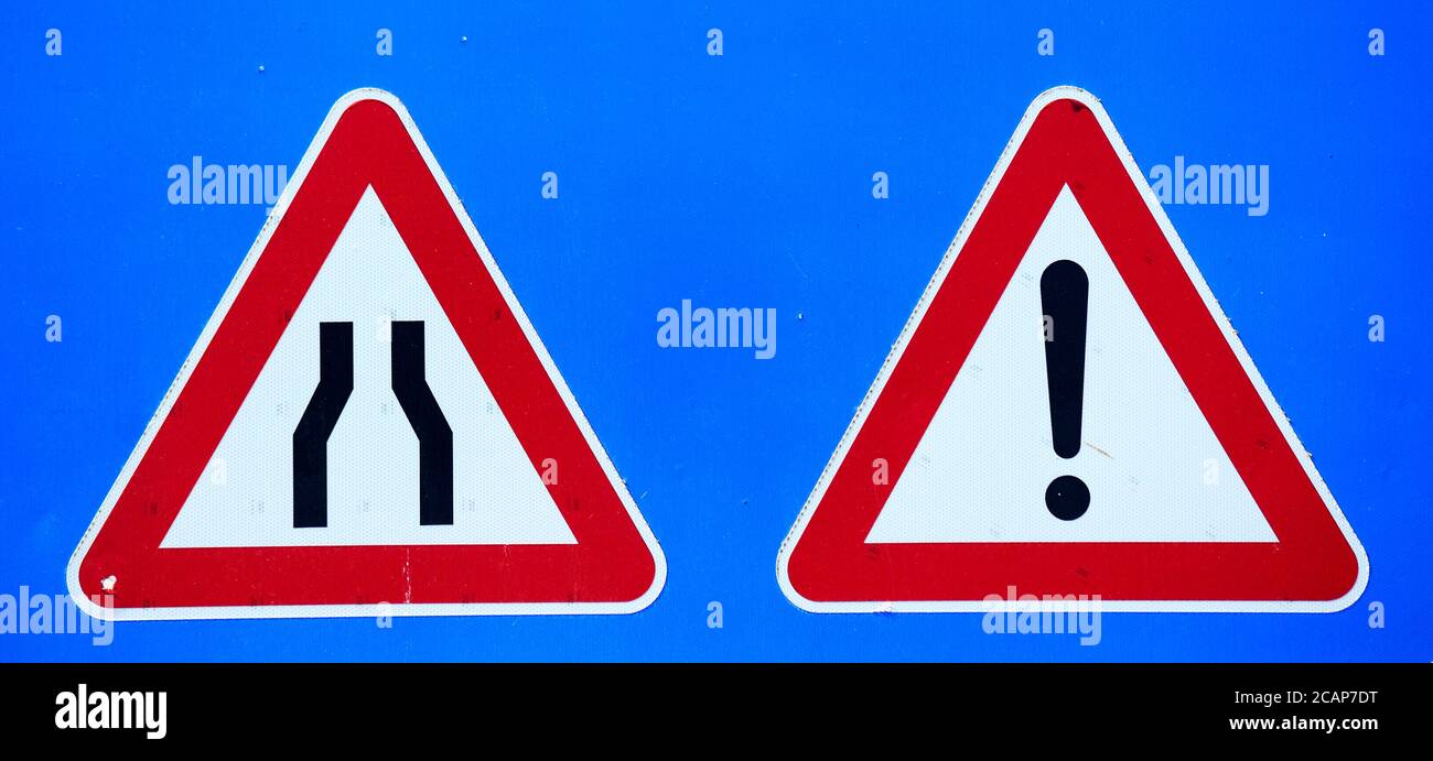 narrow road and exclamation mark signs on blue background Stock Photo ...