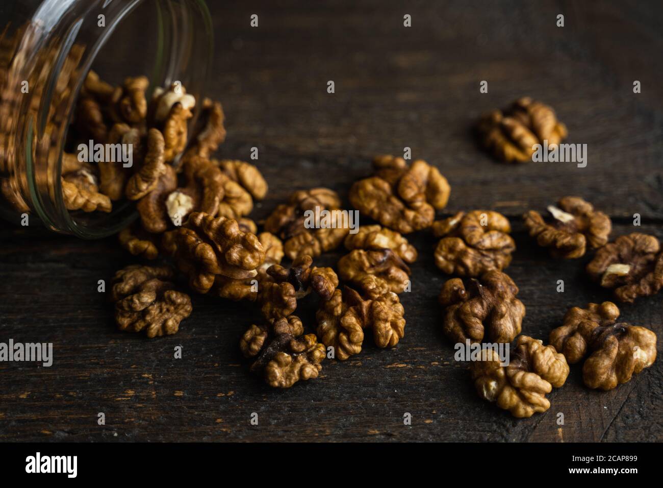 Walnut scattered on the wooden vintage table from a jar. Walnut is a ...