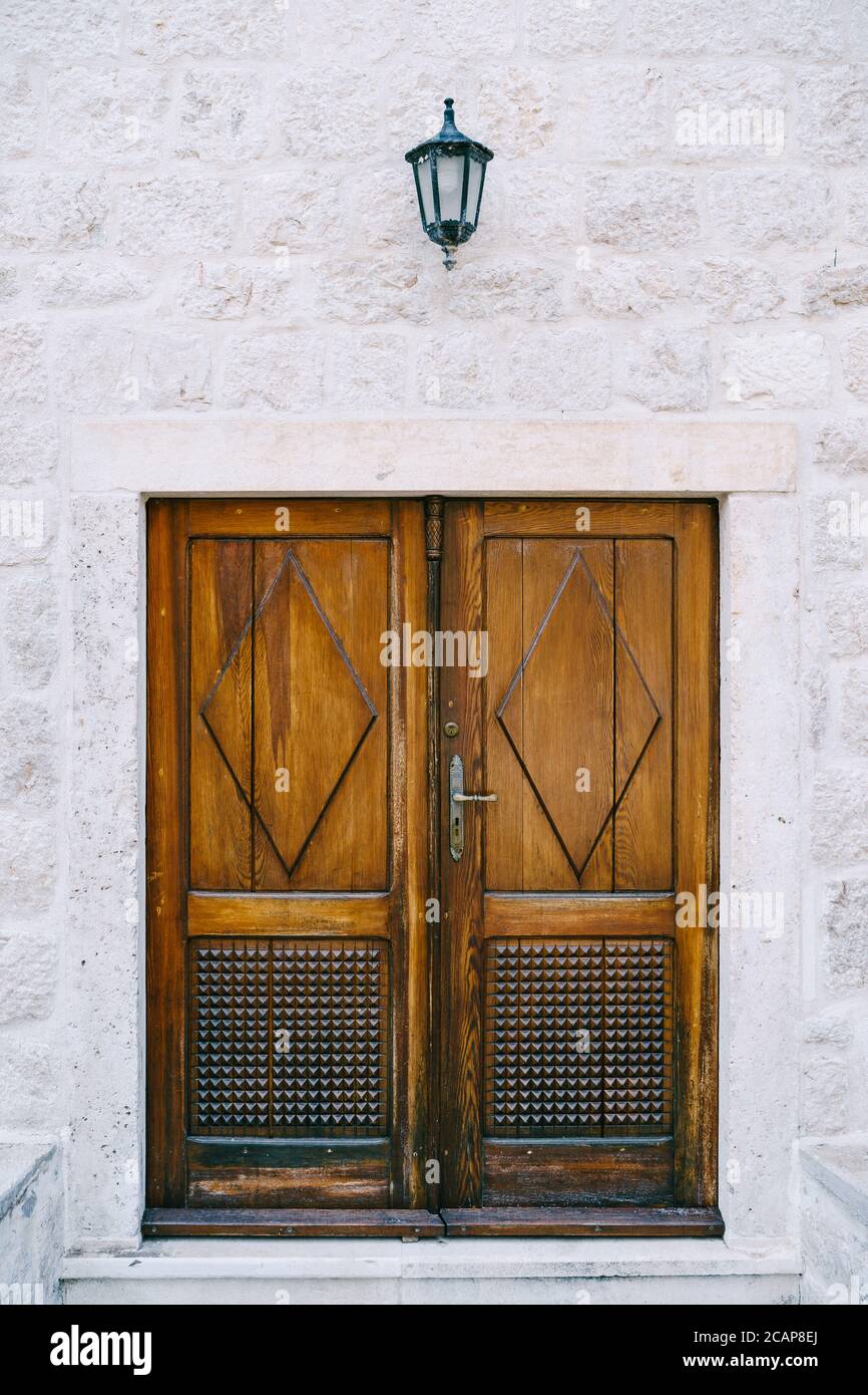 Wooden brown doors with carved elements and patterns in a white wall ...