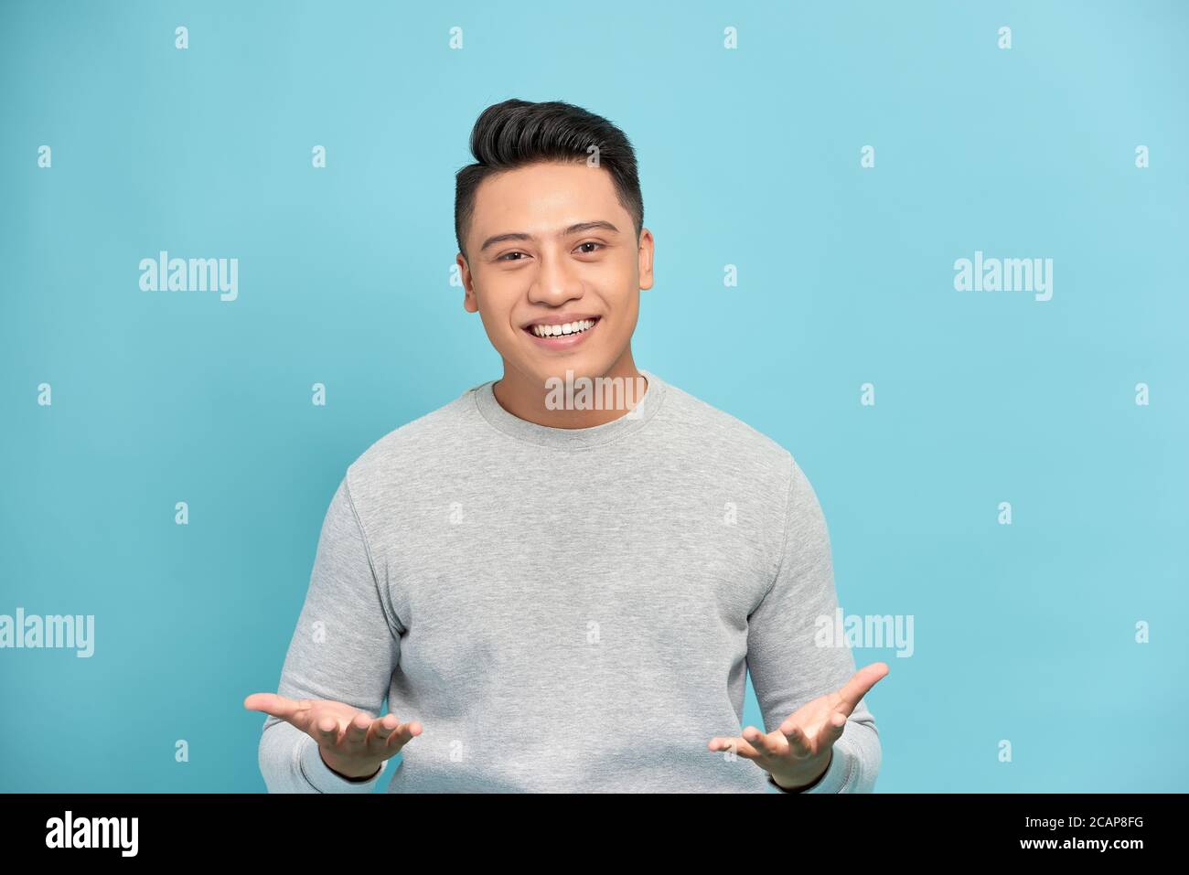 Young happy handsome Asian man raising his hands with open palms ...