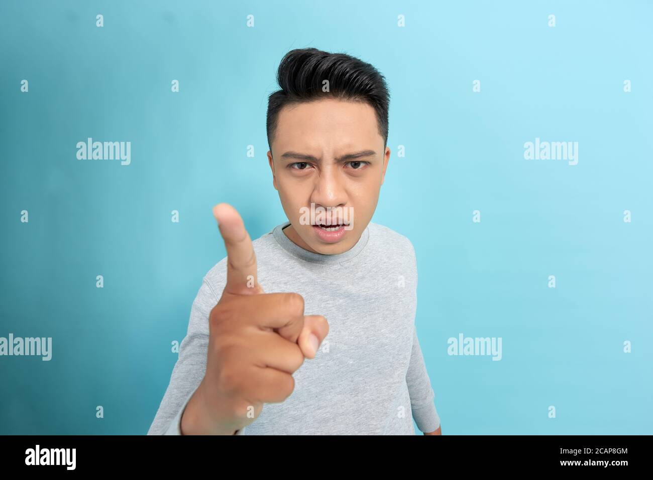 successful man angry points a finger at you, isolated on a blue ...