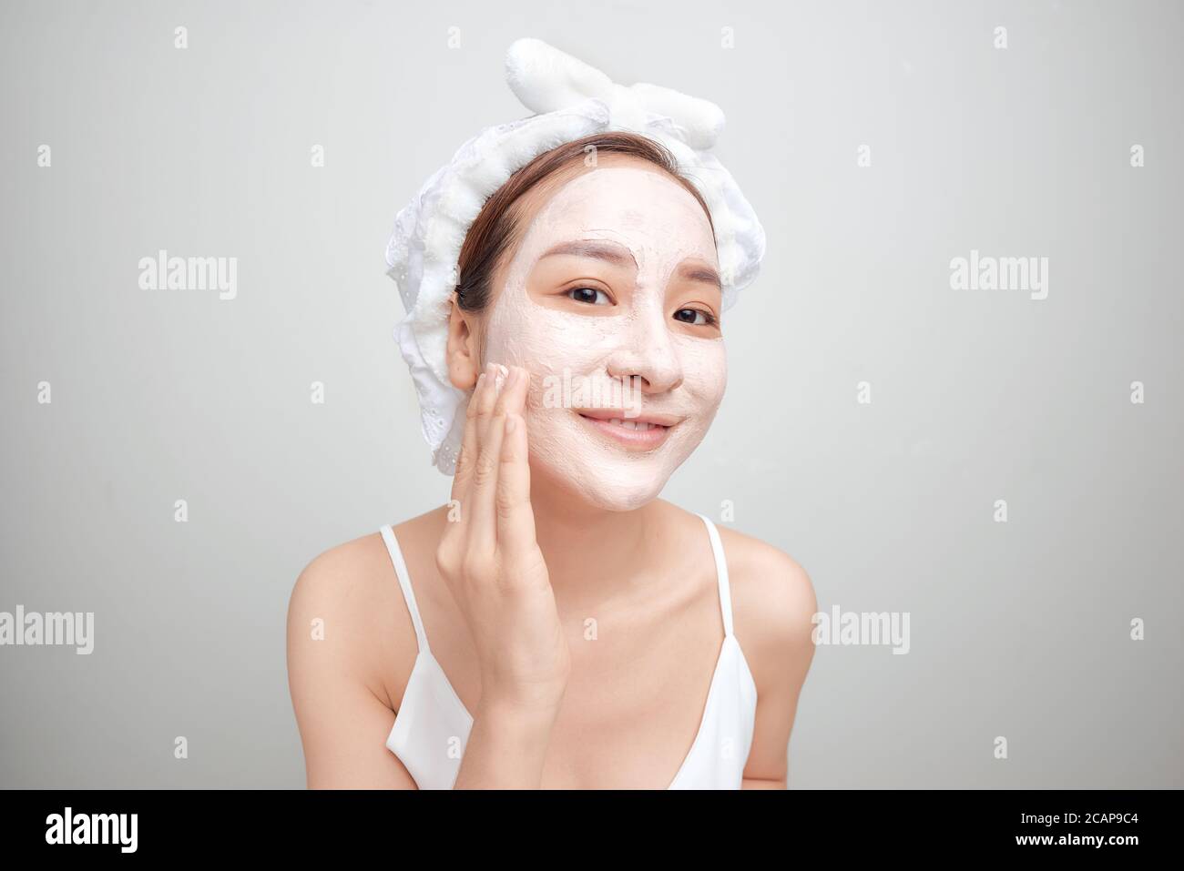Woman on a white background clean face cream on face towel in hair on ...
