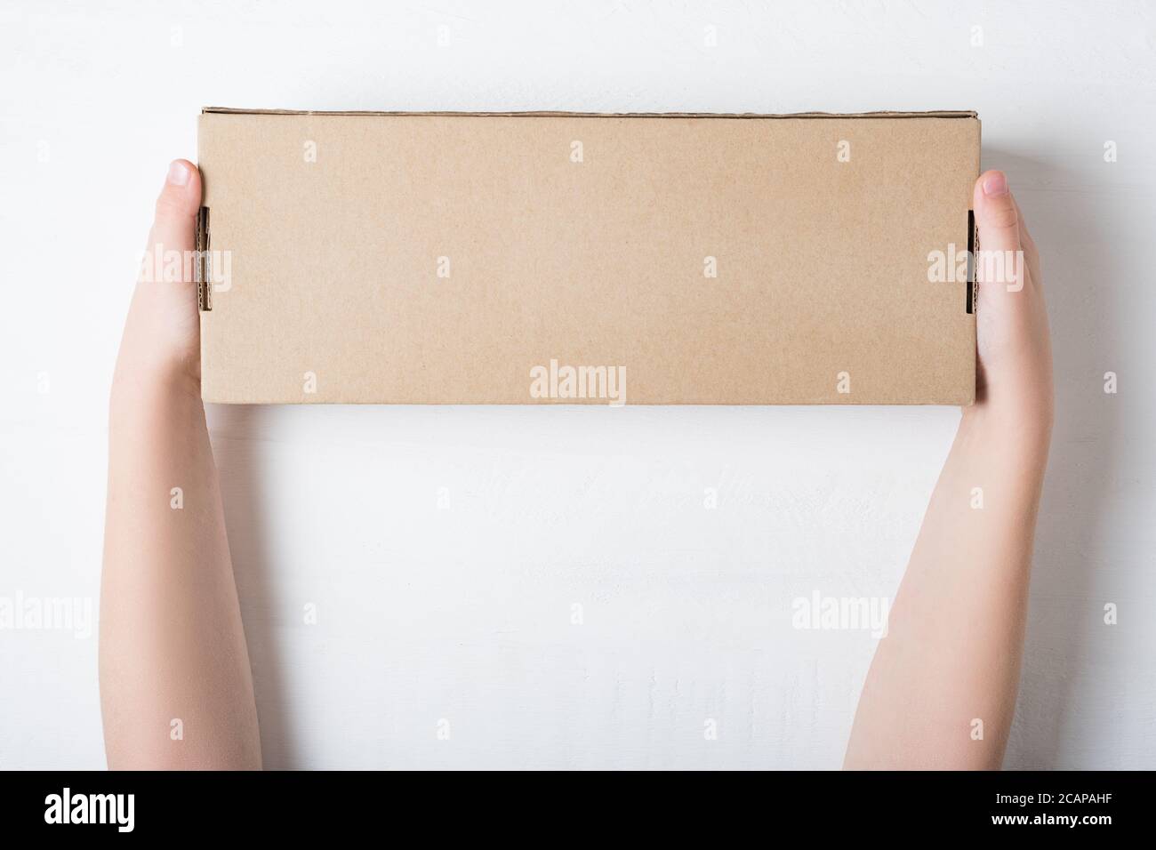 Rectangular cardboard box in children's hands. Top view, white ...