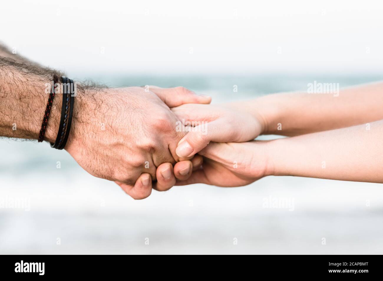 Two hands joined as a symbol of friendship with unfocused background ...