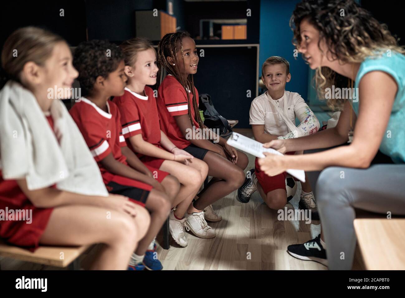 The kid's soccer team talking to their coach in a locker room Stock ...