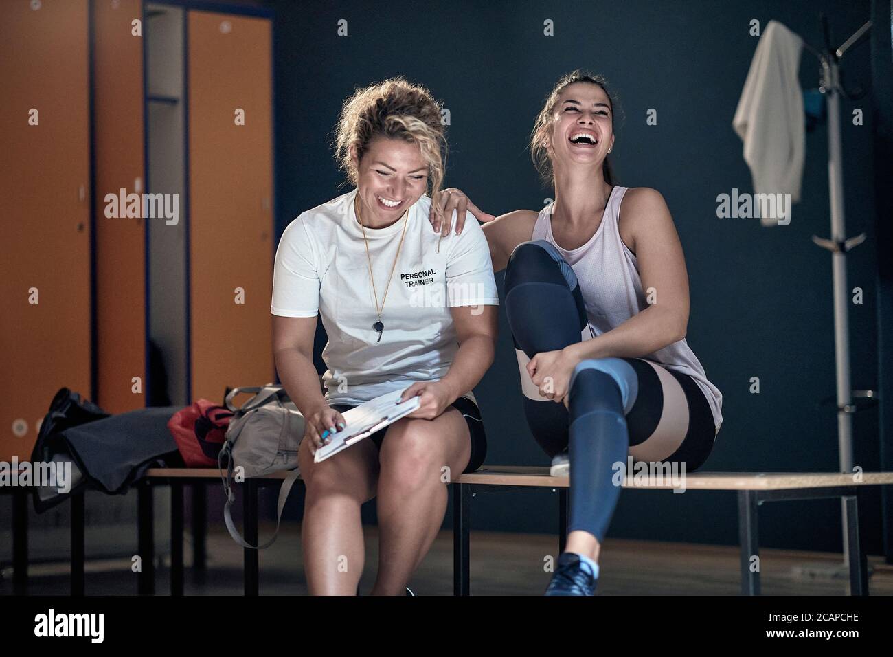 Female personal trainer and her client have good fun in a locker room ...
