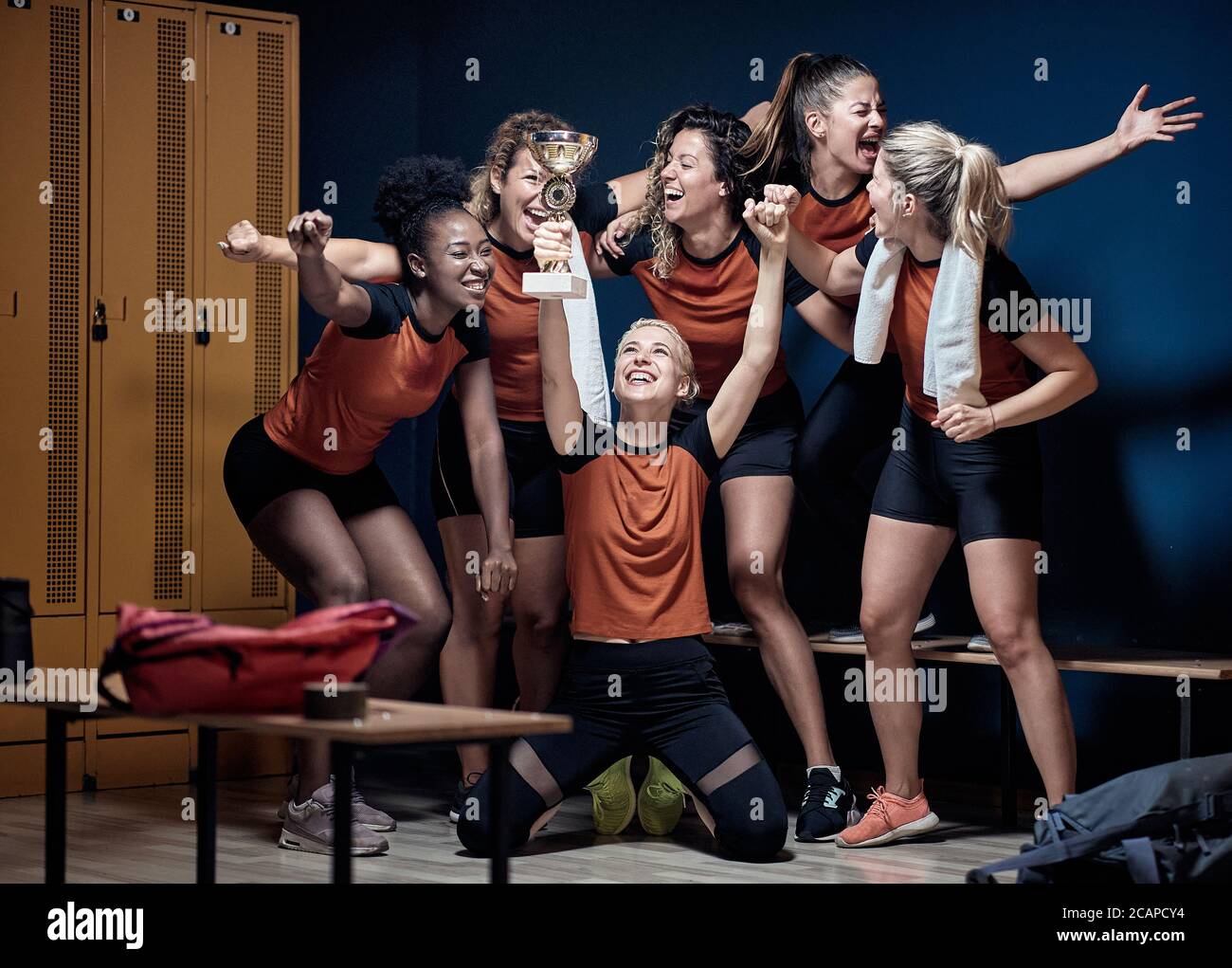 Young female team celebrating and posing in a locker room with the won ...